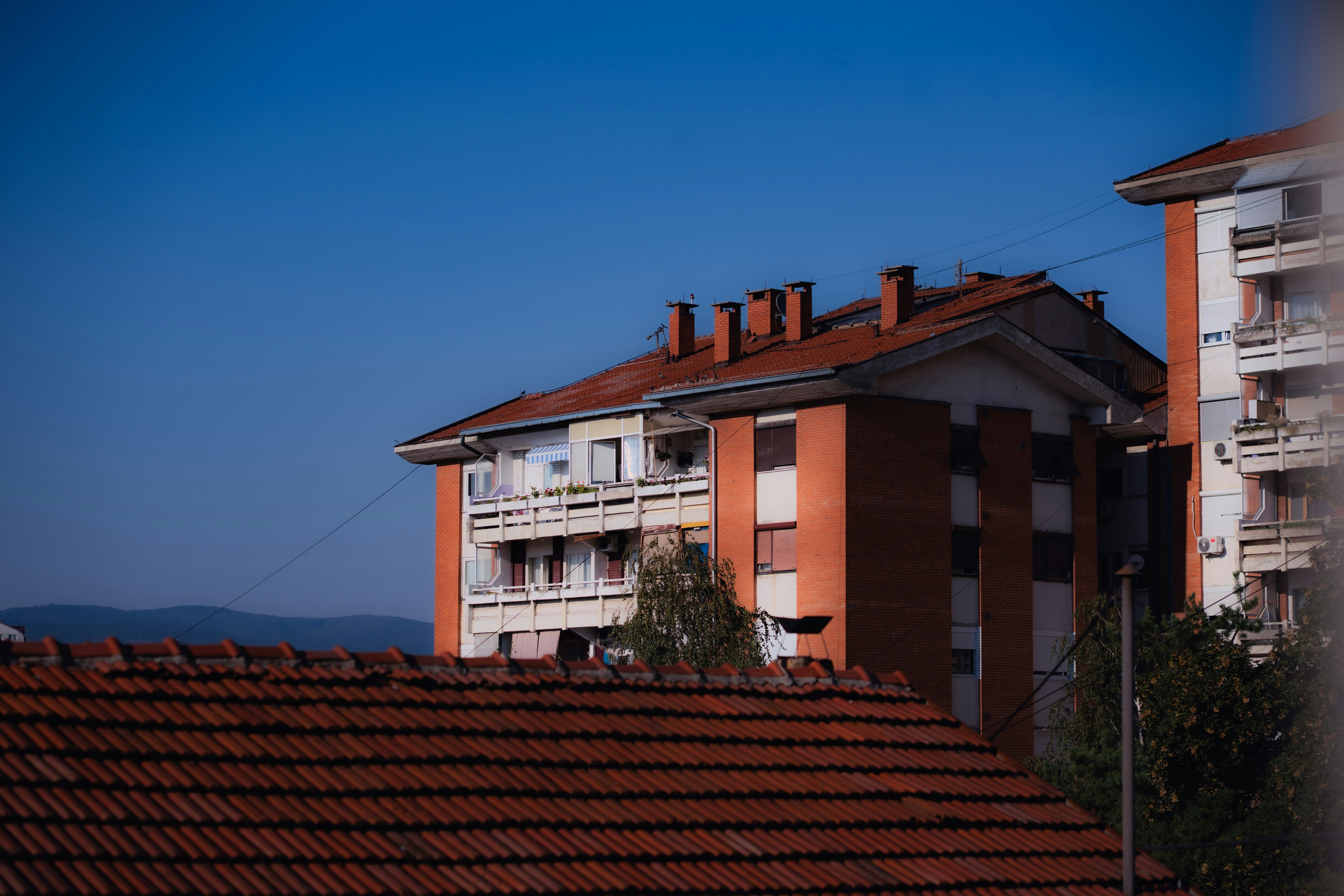 Sunlit rooftop skyline with a distant apartment block