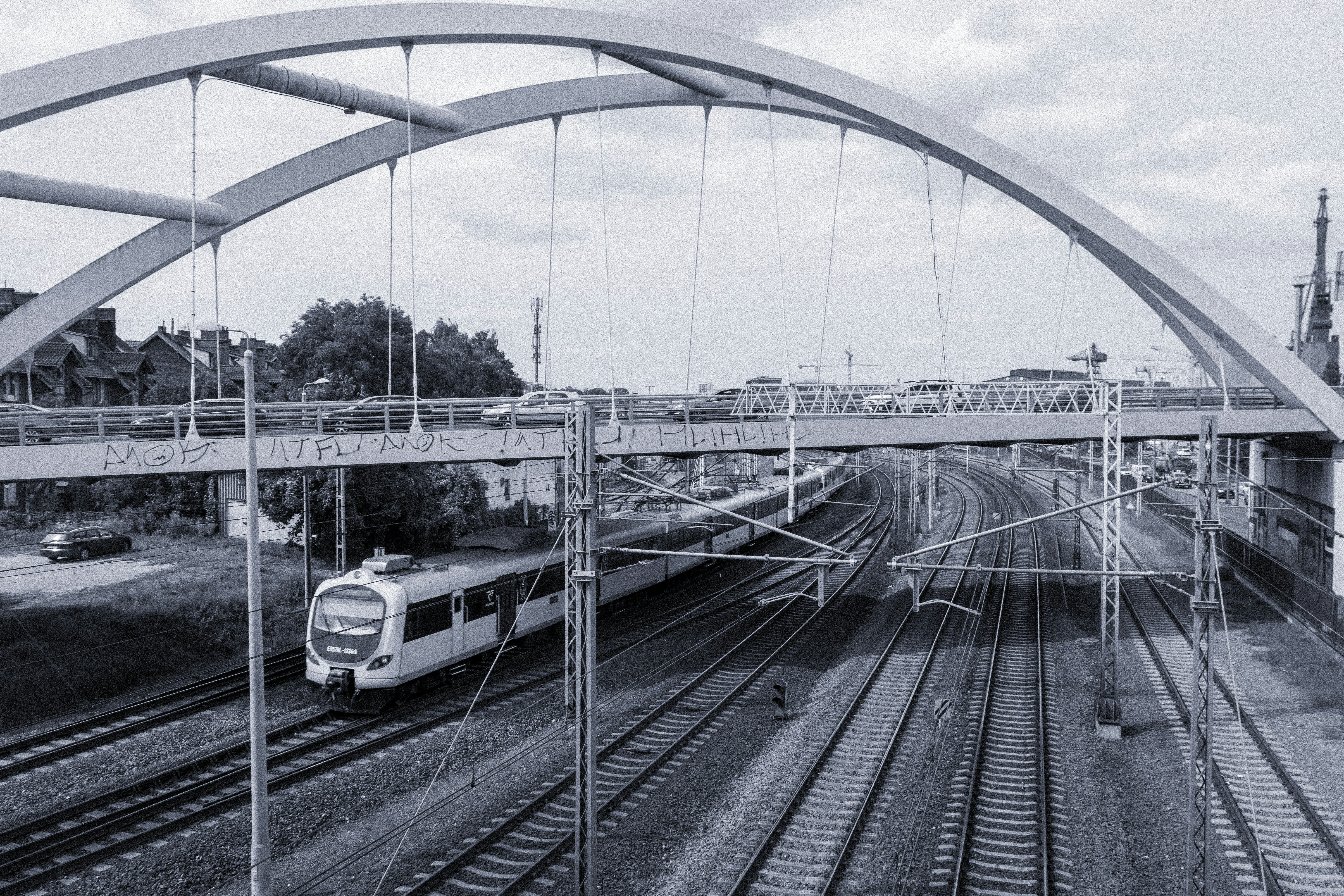 Overpass Echoes: Rails Curl Under the Arched Bridge