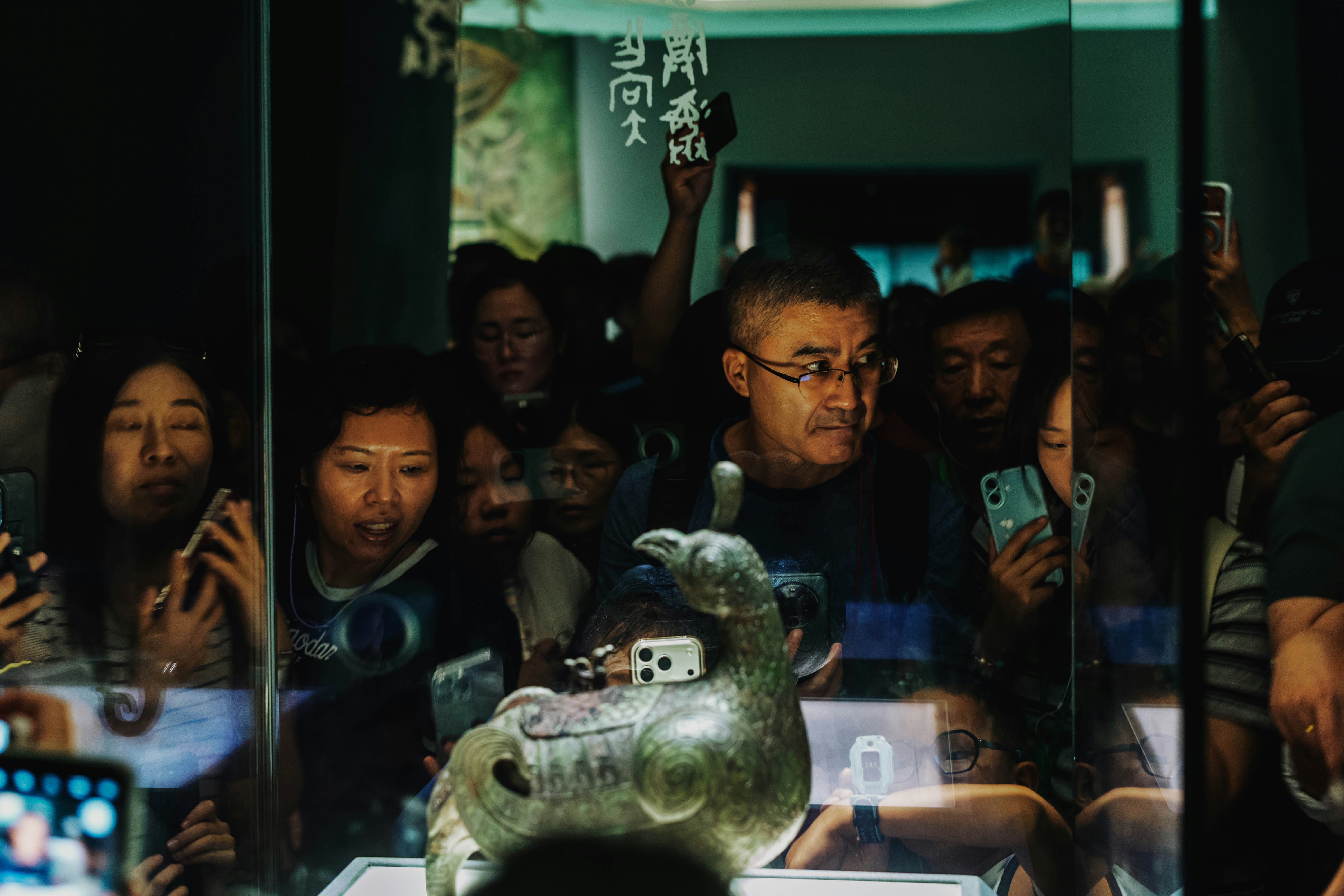 Crowd Peers Through Glass at the Tiger Hand Statue