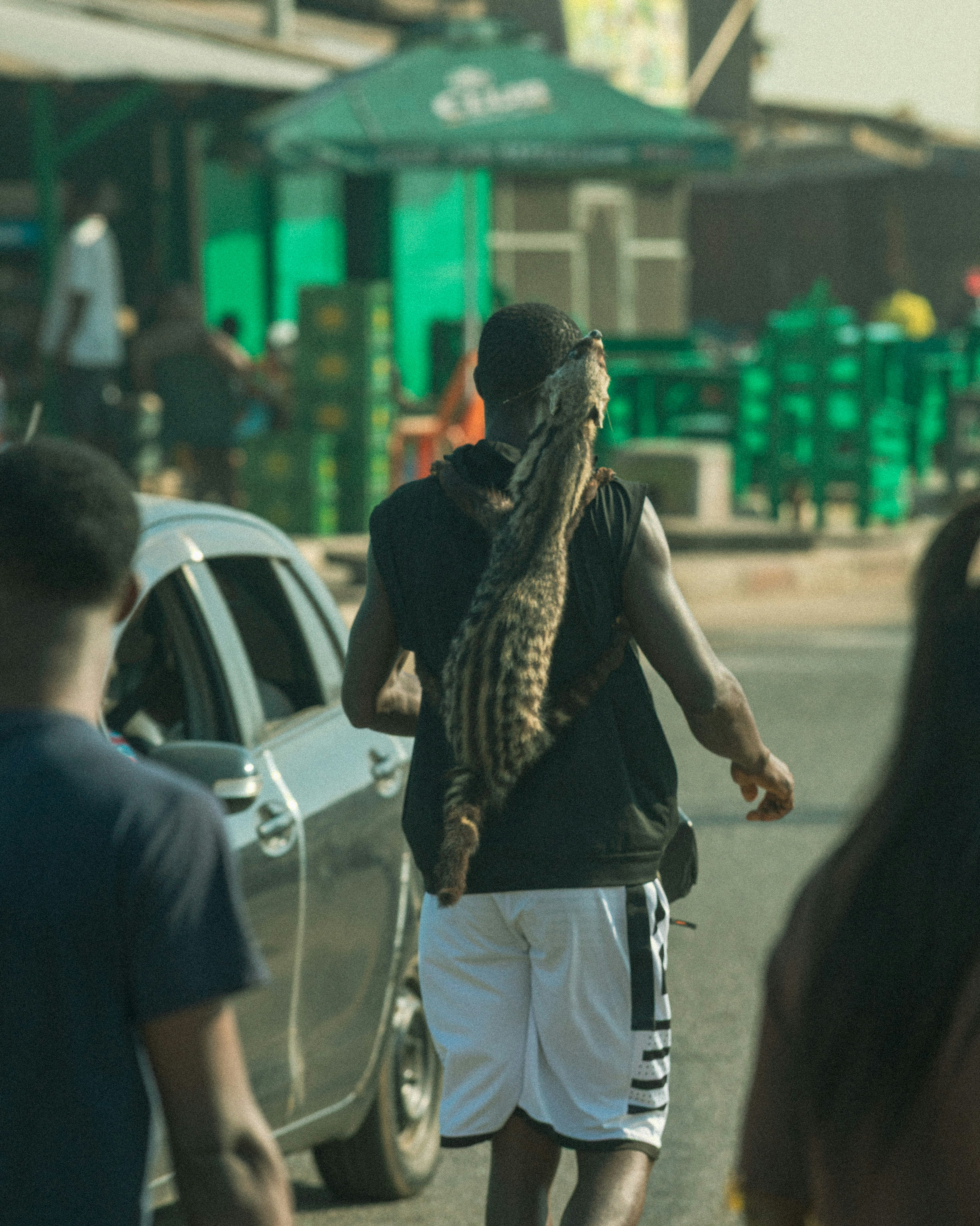 Escape in the Street: A man with a long scarf strides past a city storefront