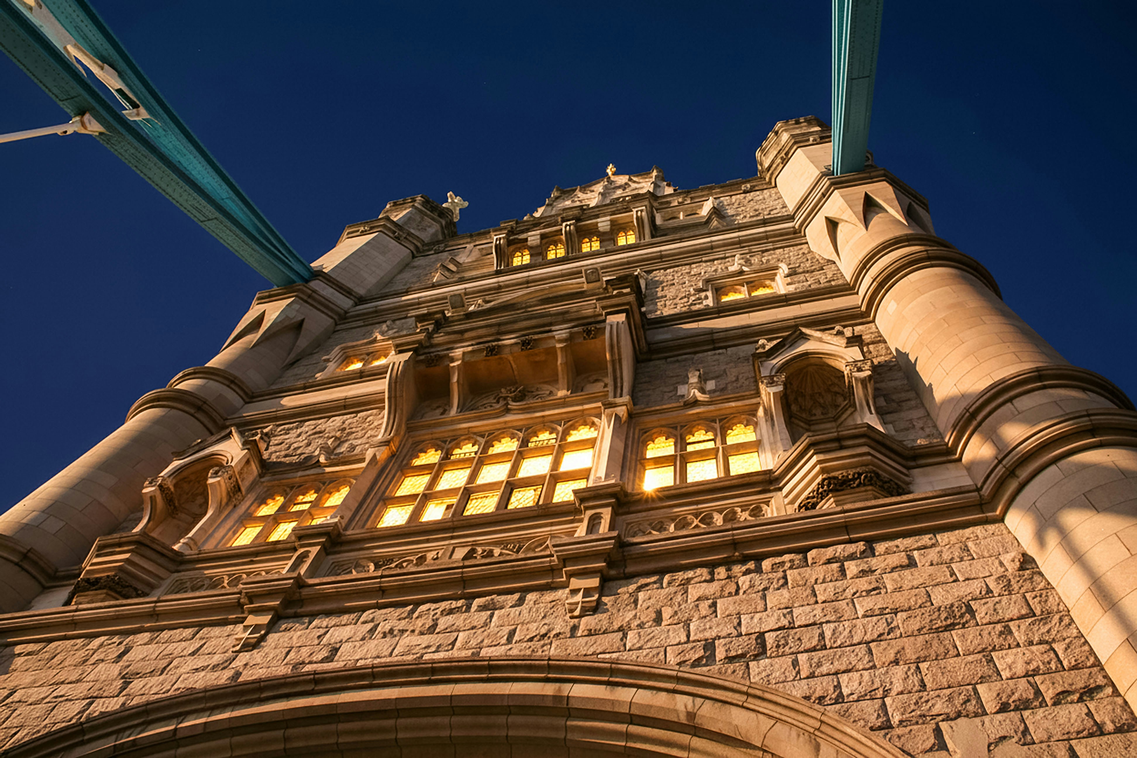 Stone Gatekeeper: A Night-Illuminated Facade Framed by Suspension Beams