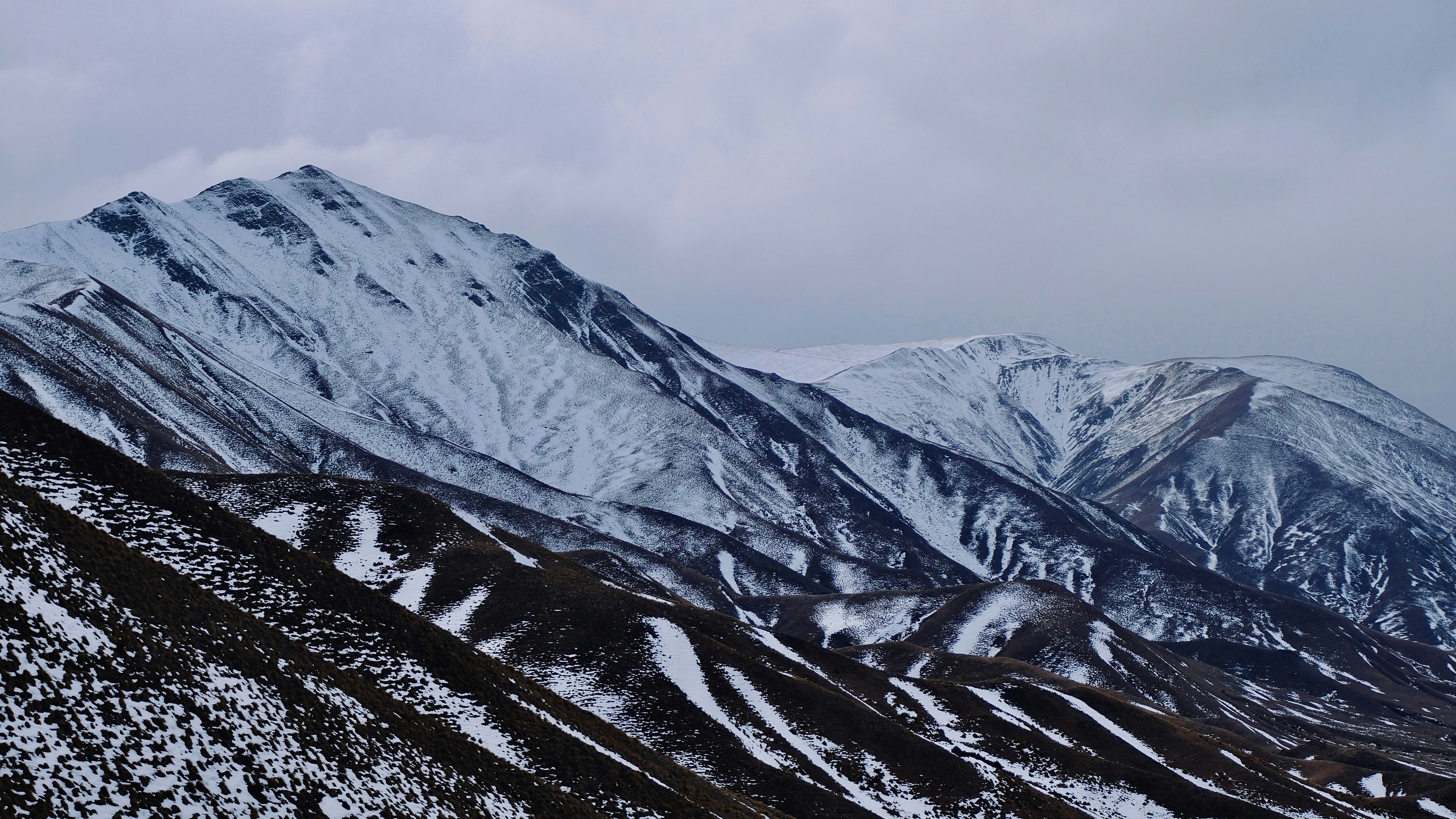 Snow-veiled ridges under a moody alpine sky