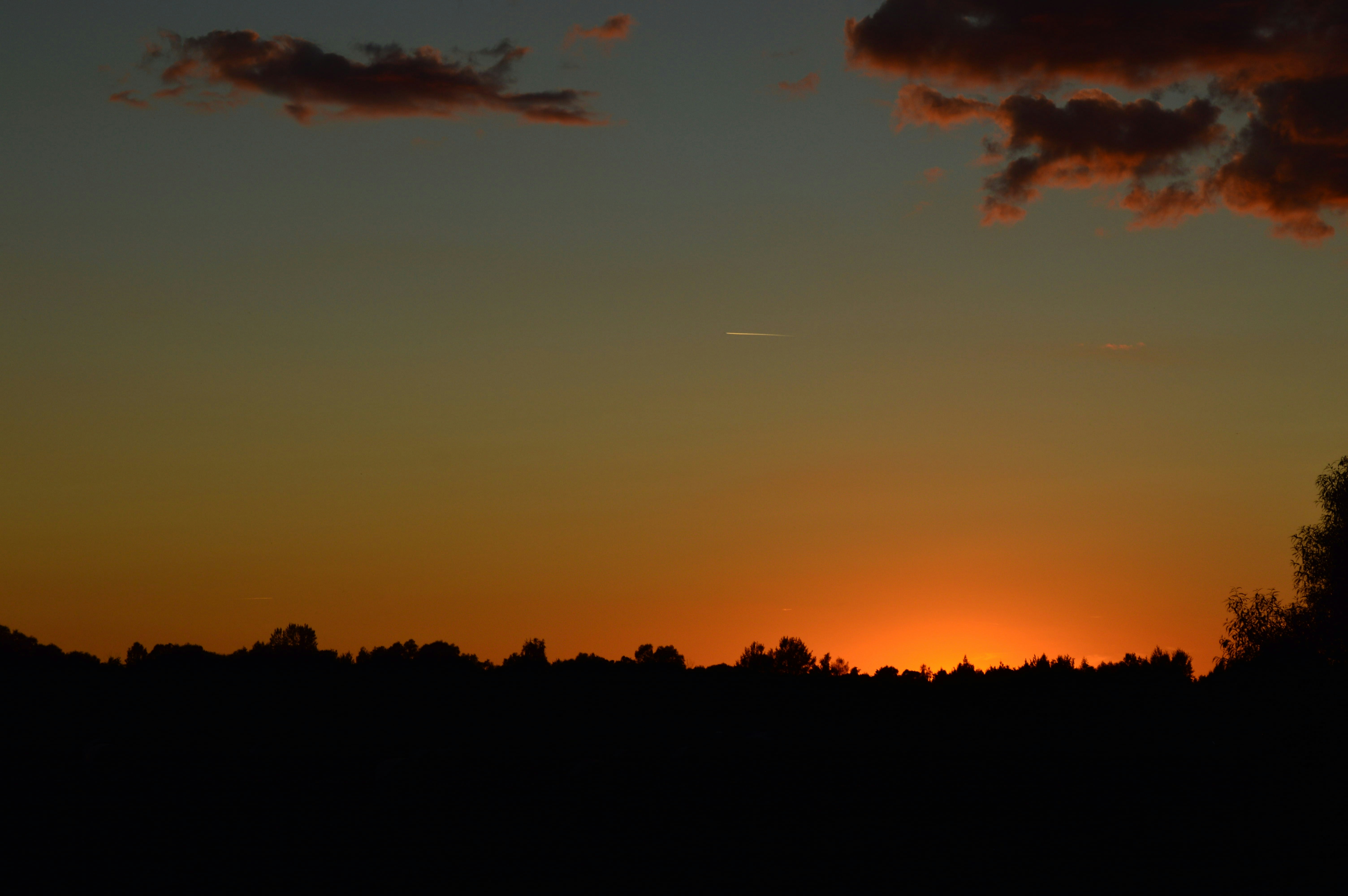 Sunset Silhouette: Horizon Line with a Faint Jet Across the Sky