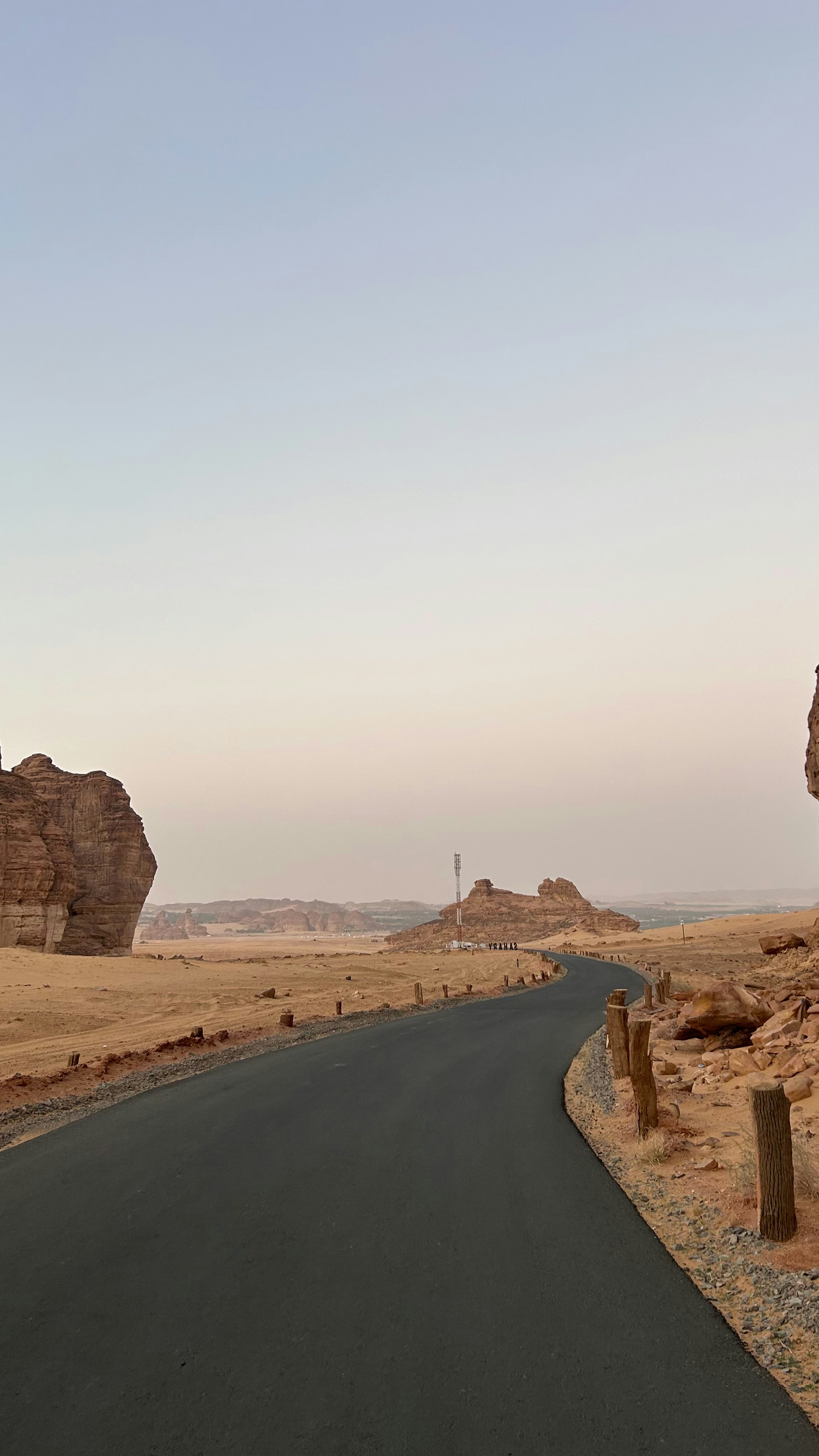 A paved road winding through a desert landscape with large sandstone rock formations