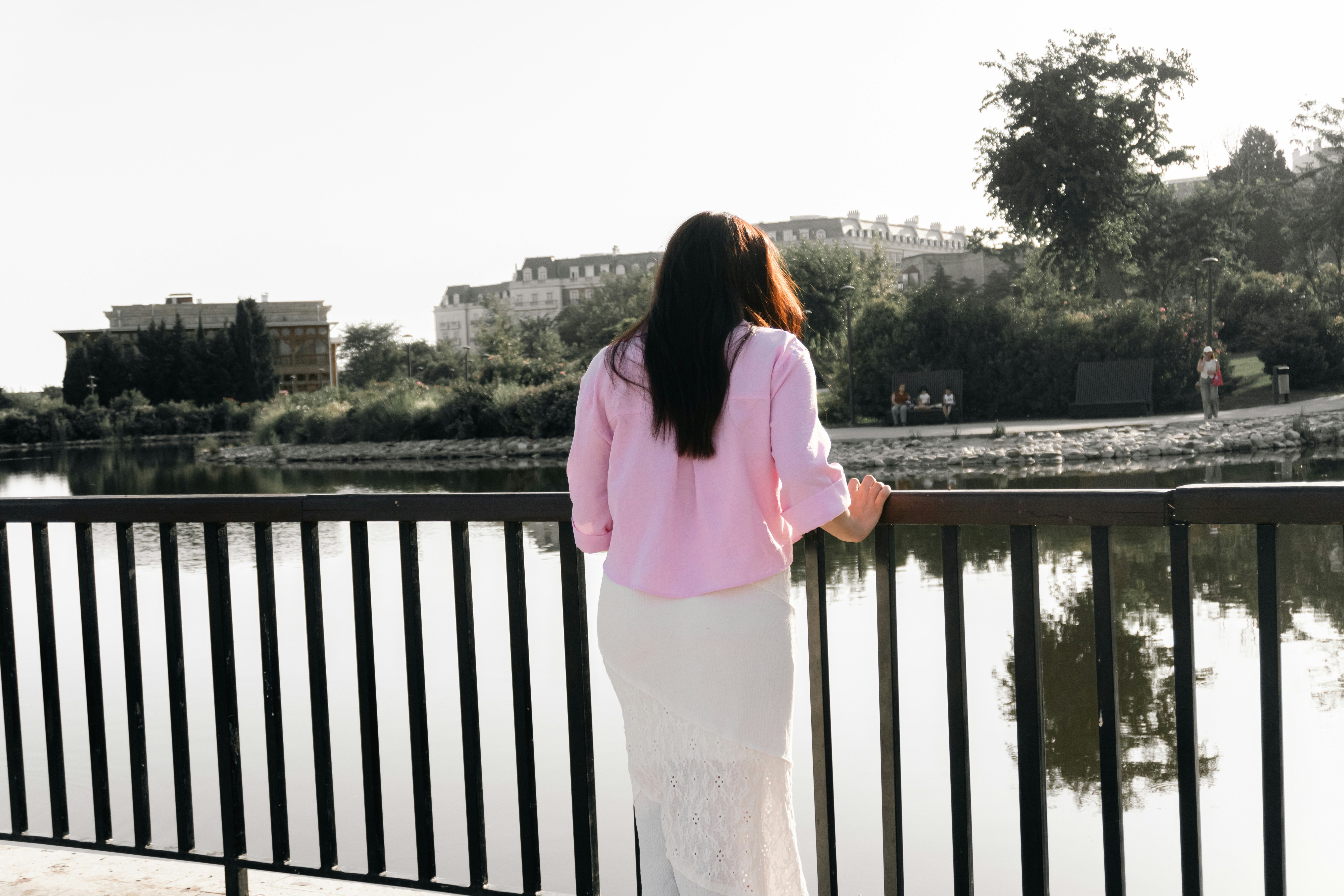 Azure Horizon: A Woman in Pink by the Riverside Rail