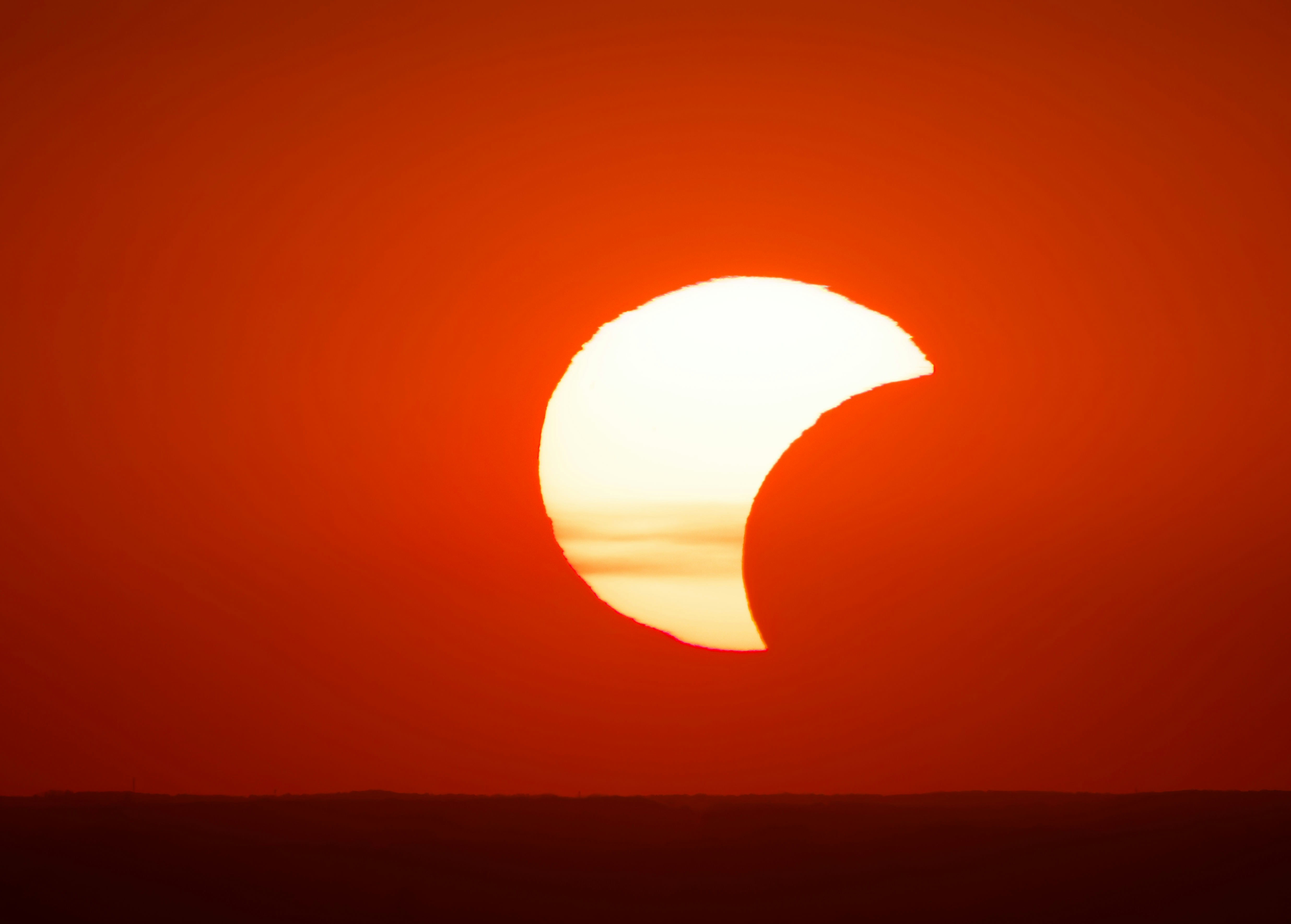 Crimson Crescent: a solar bite carved from a desert horizon