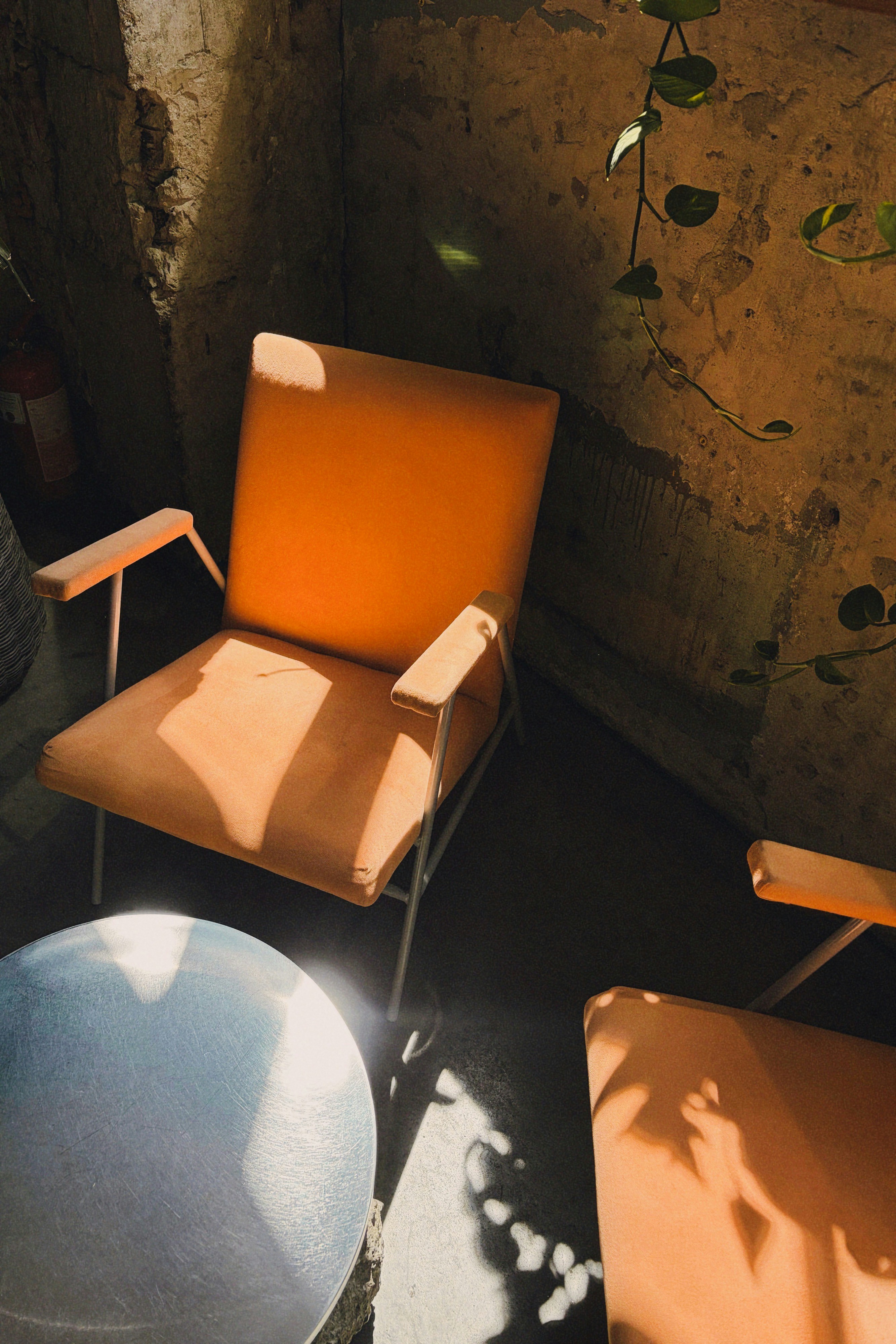Sunlit Terrace: Orange Chairs and a Shadowed Table