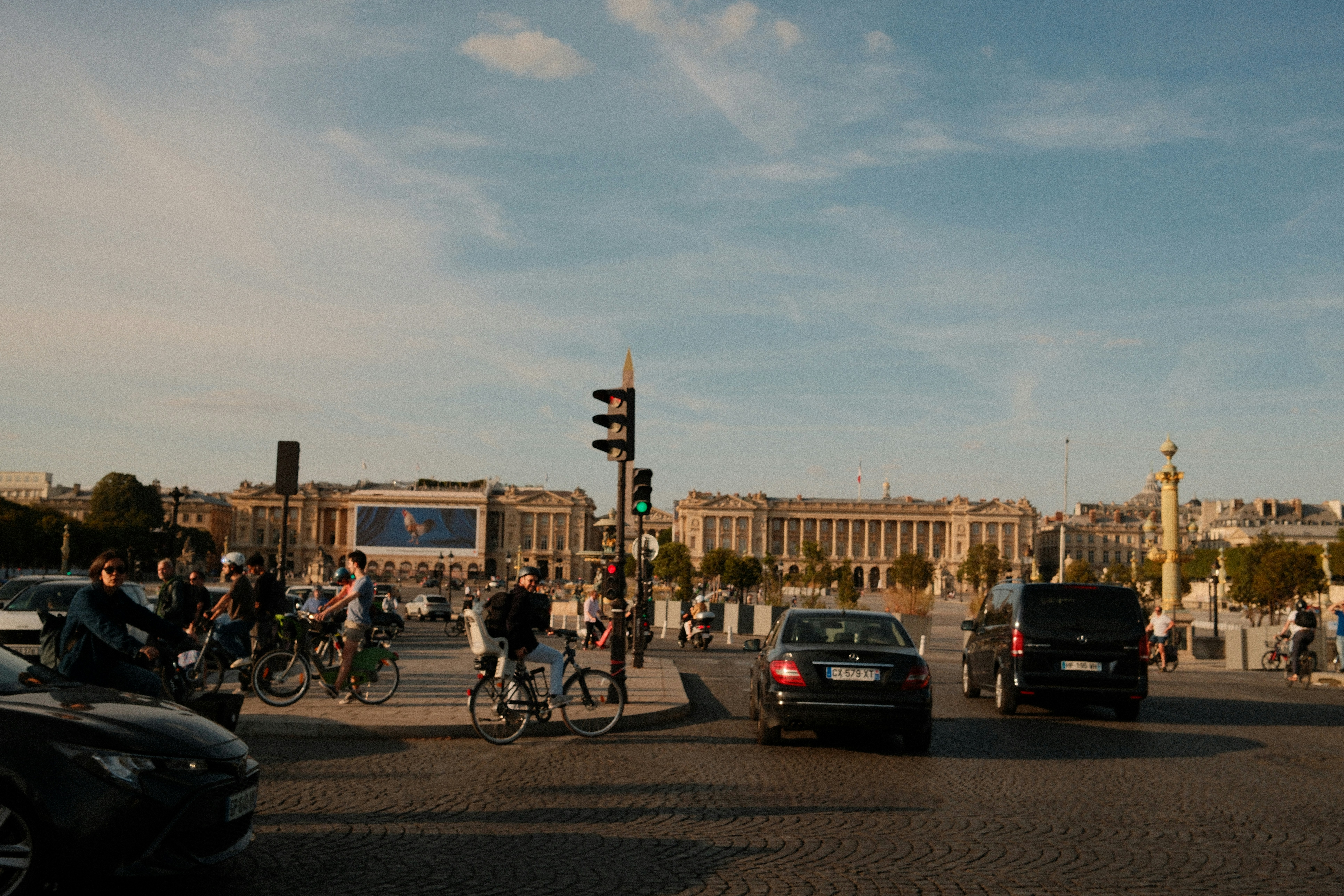 Crossroads of City Life at Dusk: Bicycles, Cars, and a Timeless Arch
