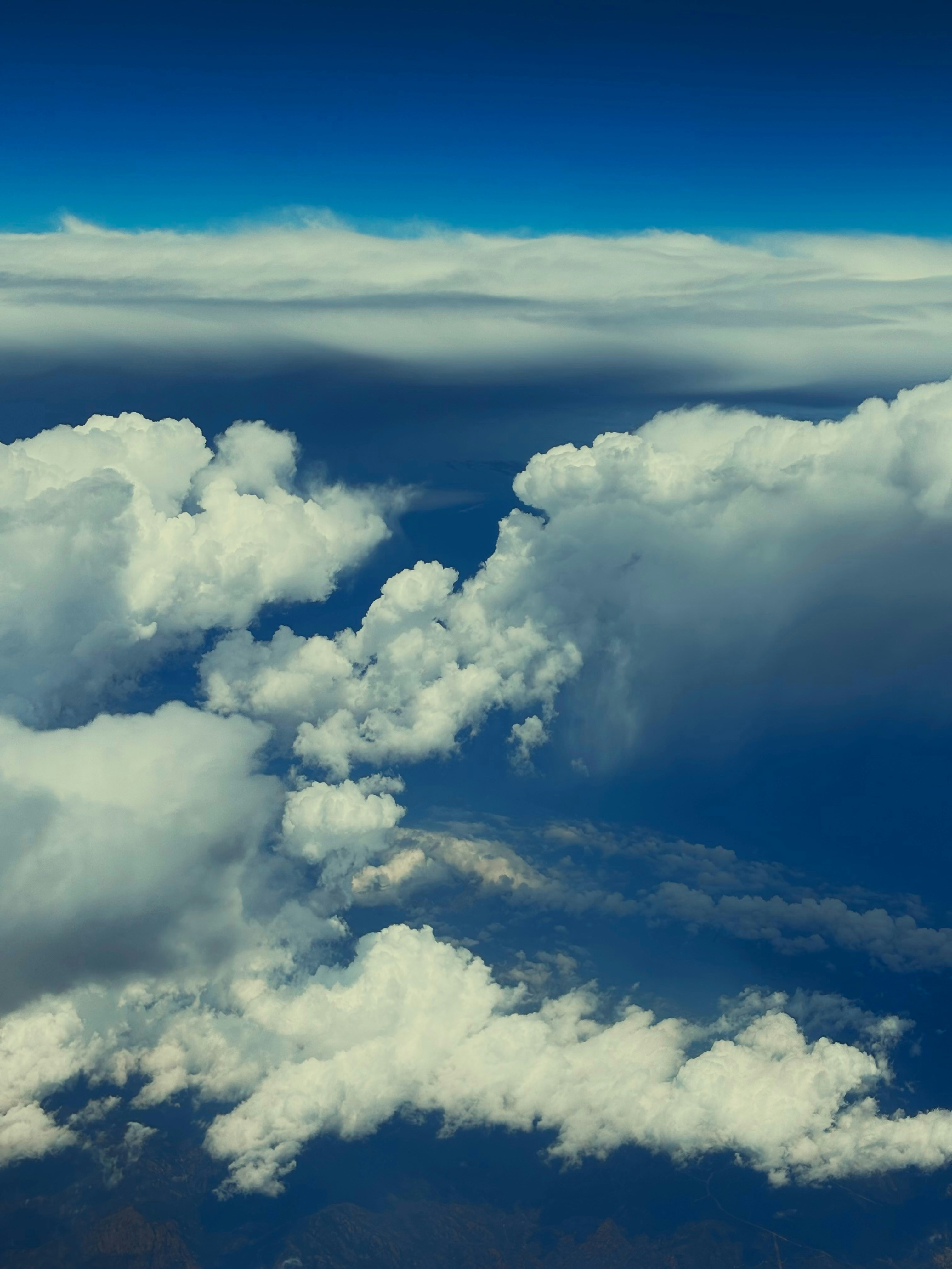 Vast sky featuring layered clouds against a deep blue backdrop, emphasizing altitude and distance with soft, billowy formations.