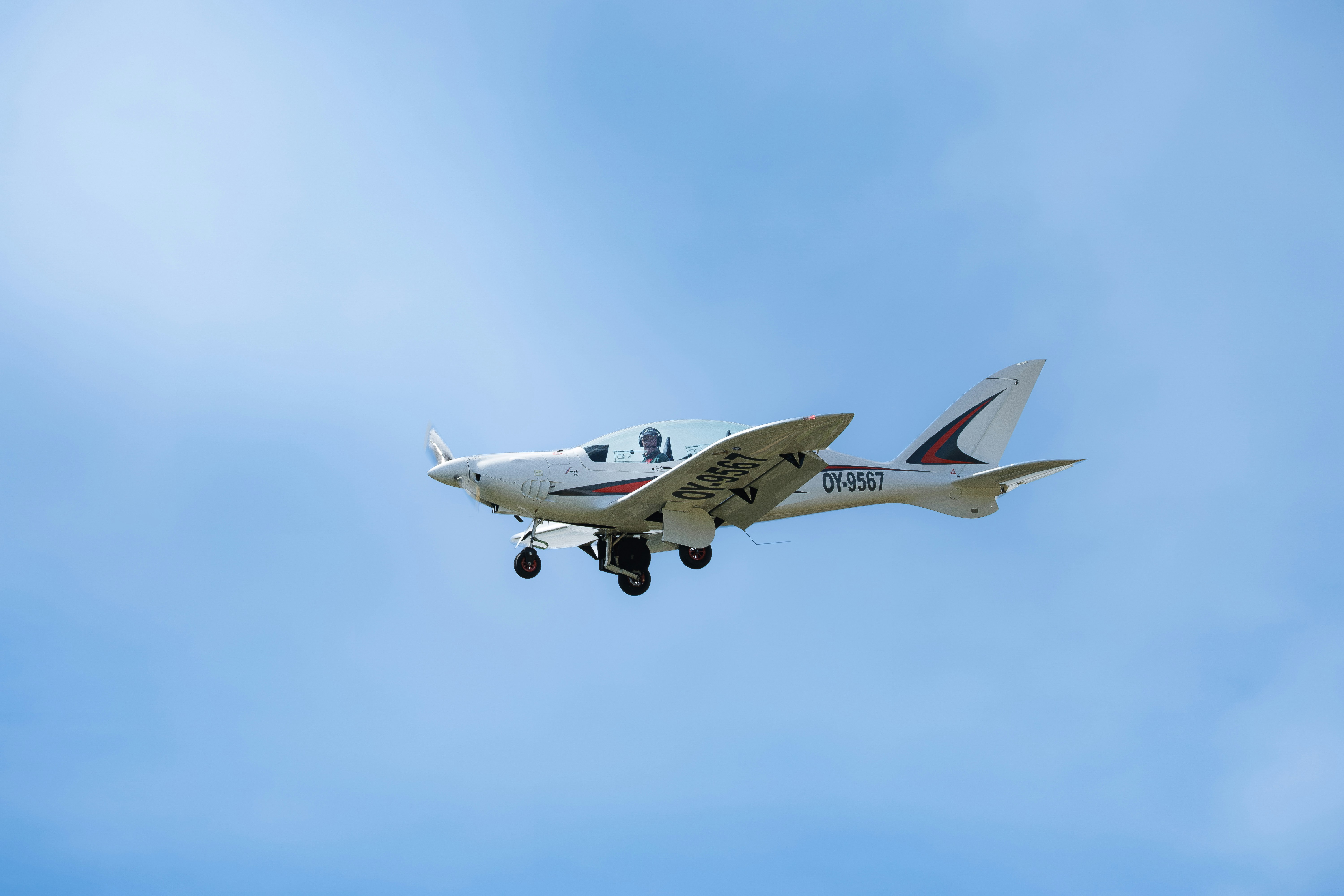 White glider in a pale blue sky: midflight over a tranquil horizon