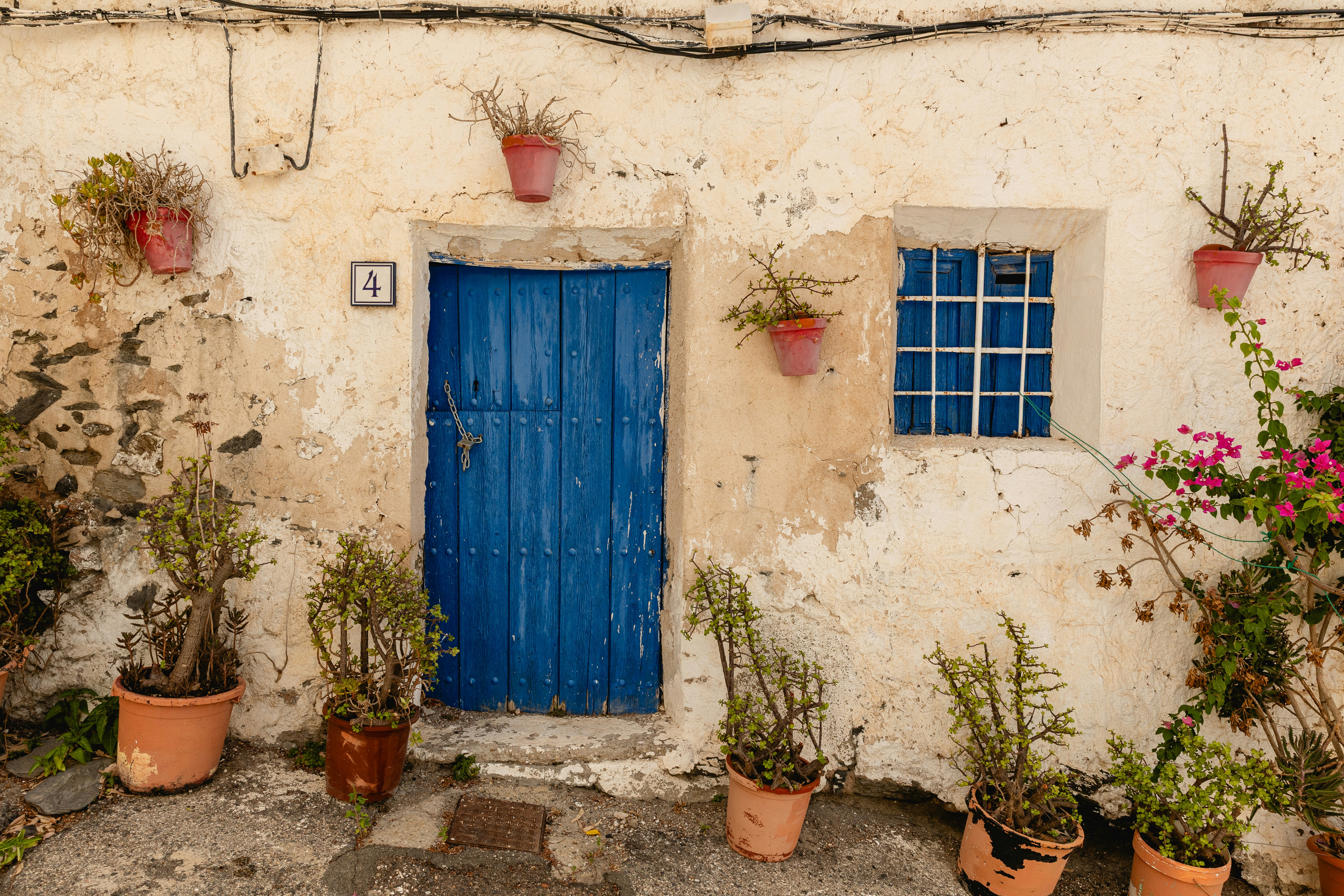 Blue Door Portrait: a sunlit Mediterranean Facade Framed by Clay Pots