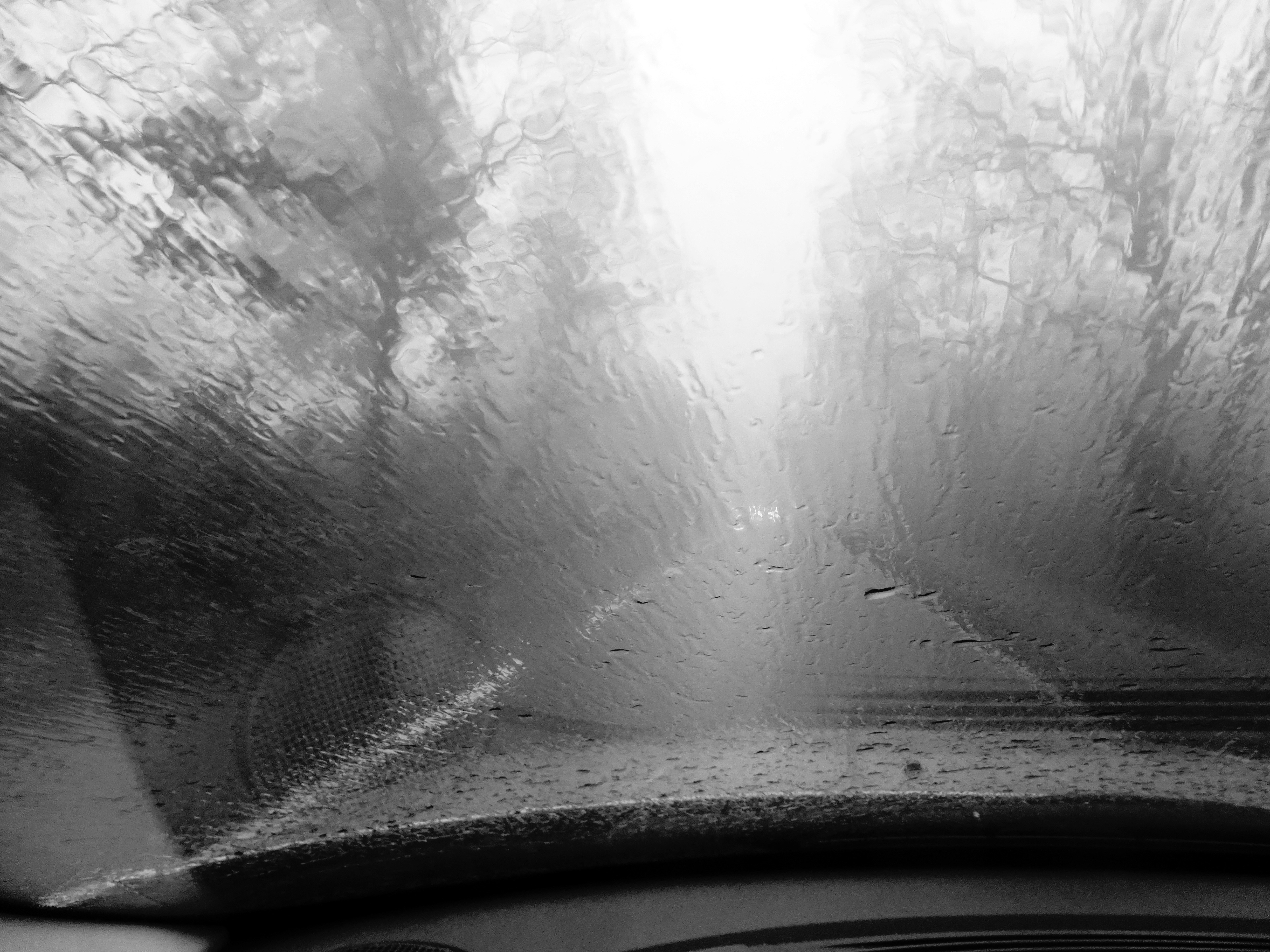 Rain-swept windshield into a misty road