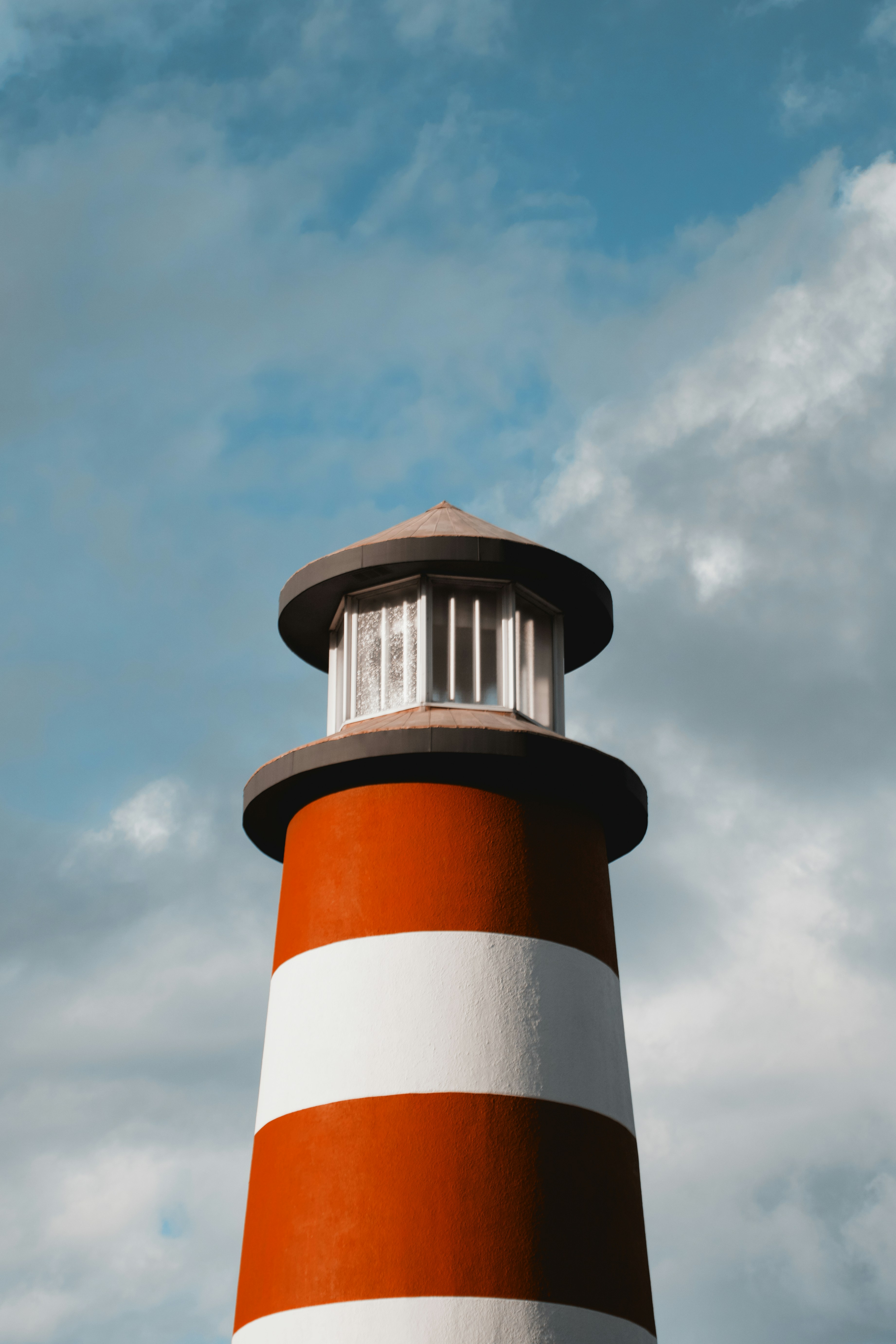 Striped beacon against the sky: a lighthouse rises over a blue backdrop