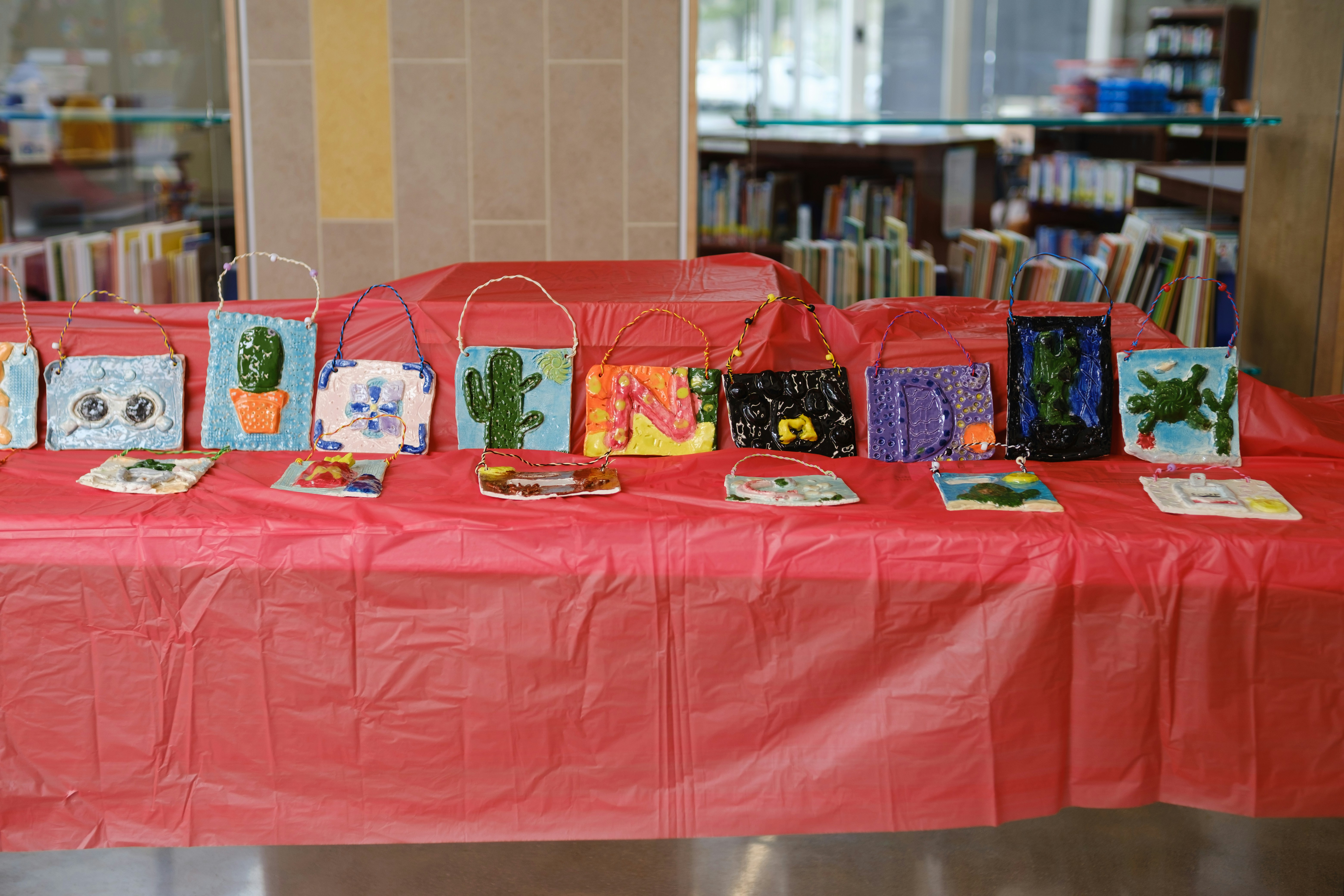 Colorful handcrafted gift bags line a red fabric display