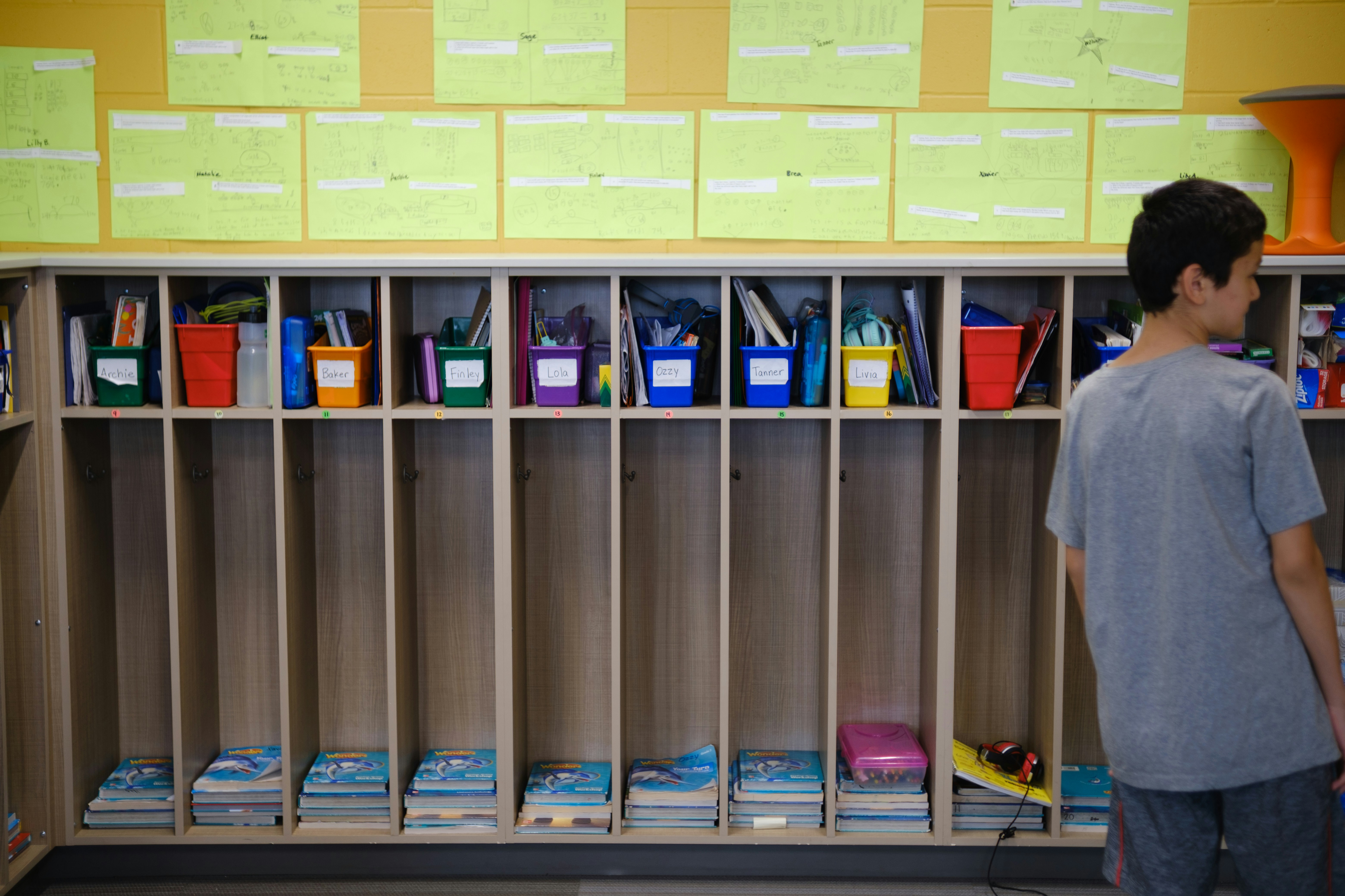 Student in front of organized cubbies and bright notes