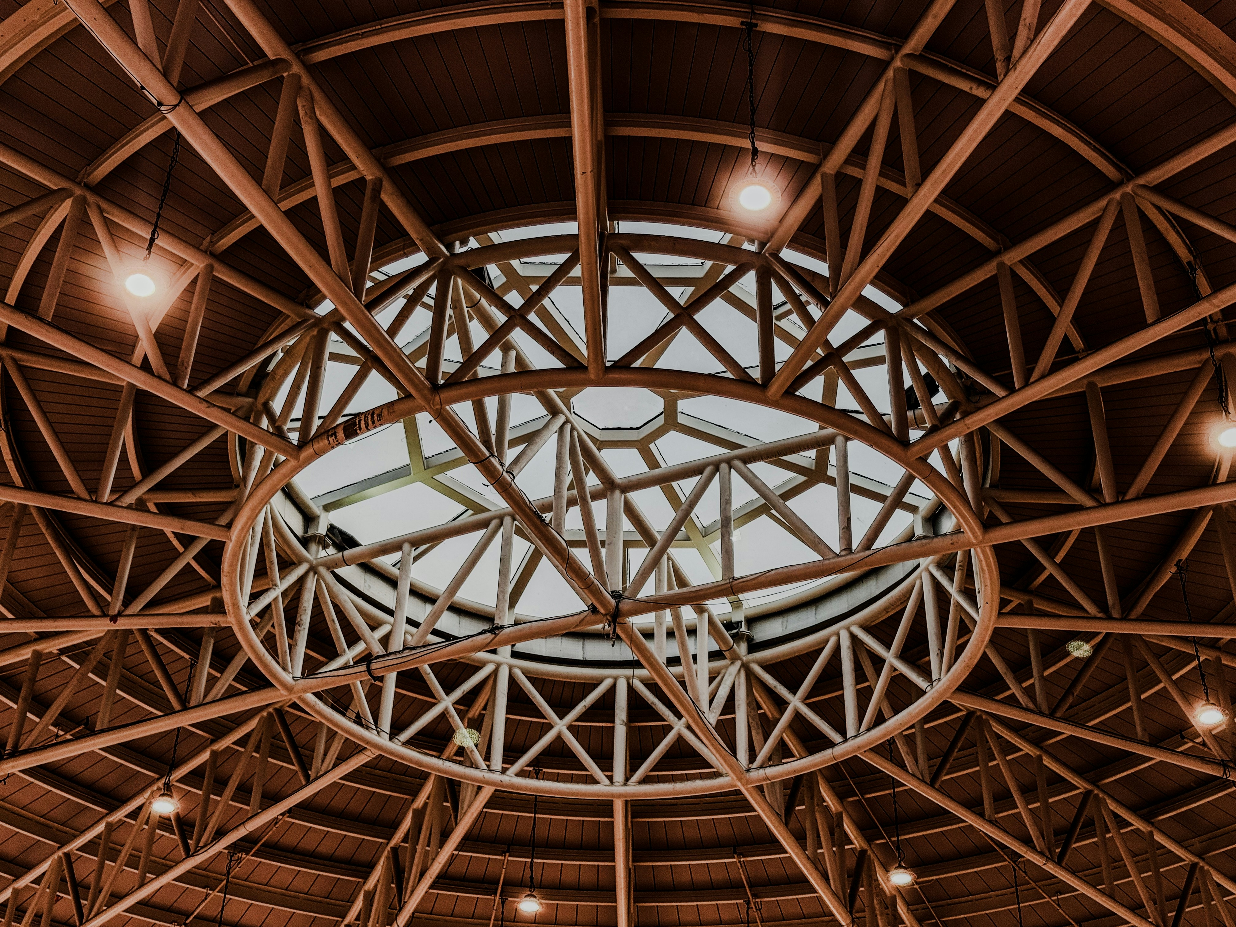 Circular lattice of steel ribs converging toward a skylight