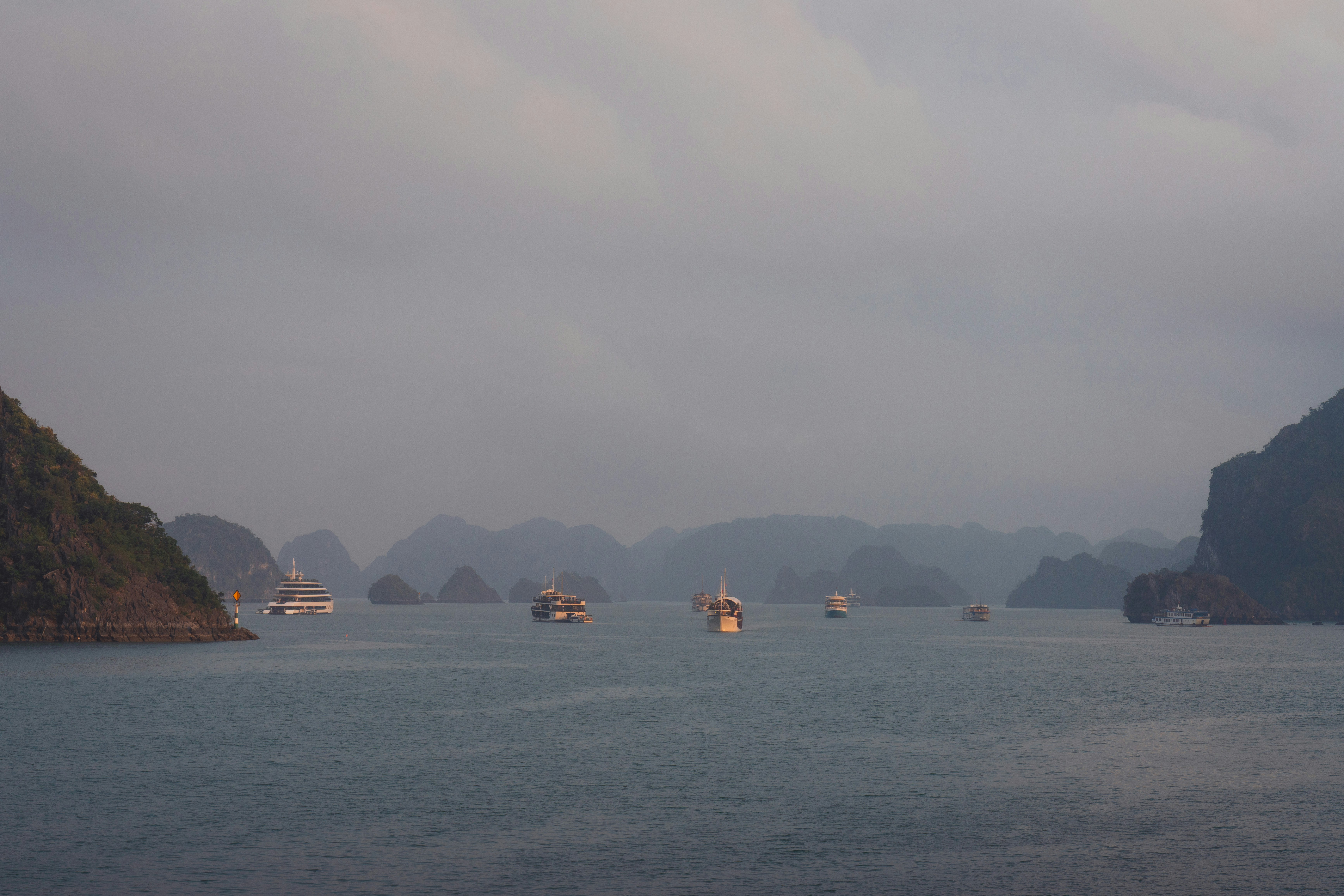 Fleet of Lantern-like Boats Amid Misty Gulf Peaks