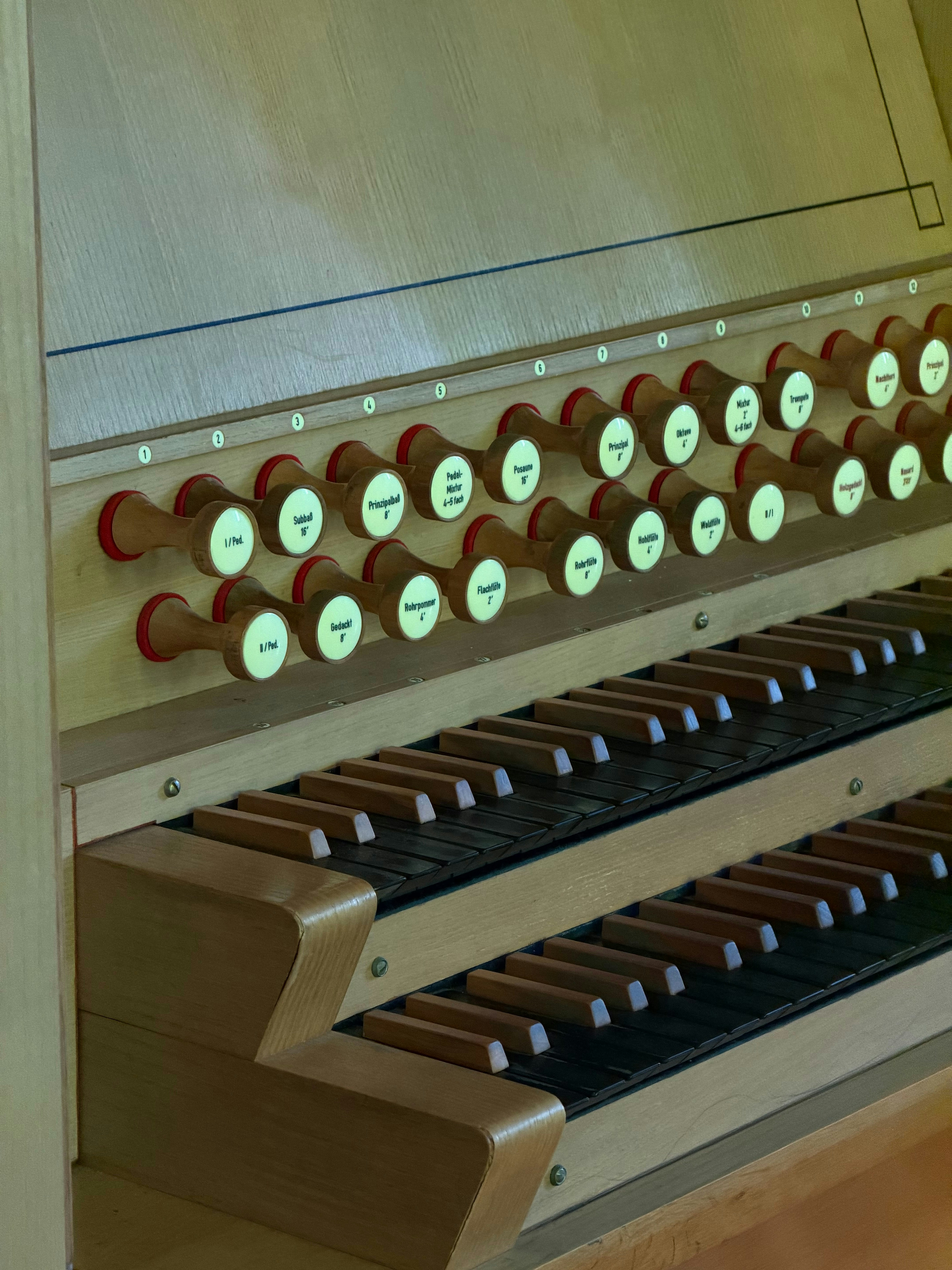Wooden organ console: rows of stops and keys beneath a gentle glow