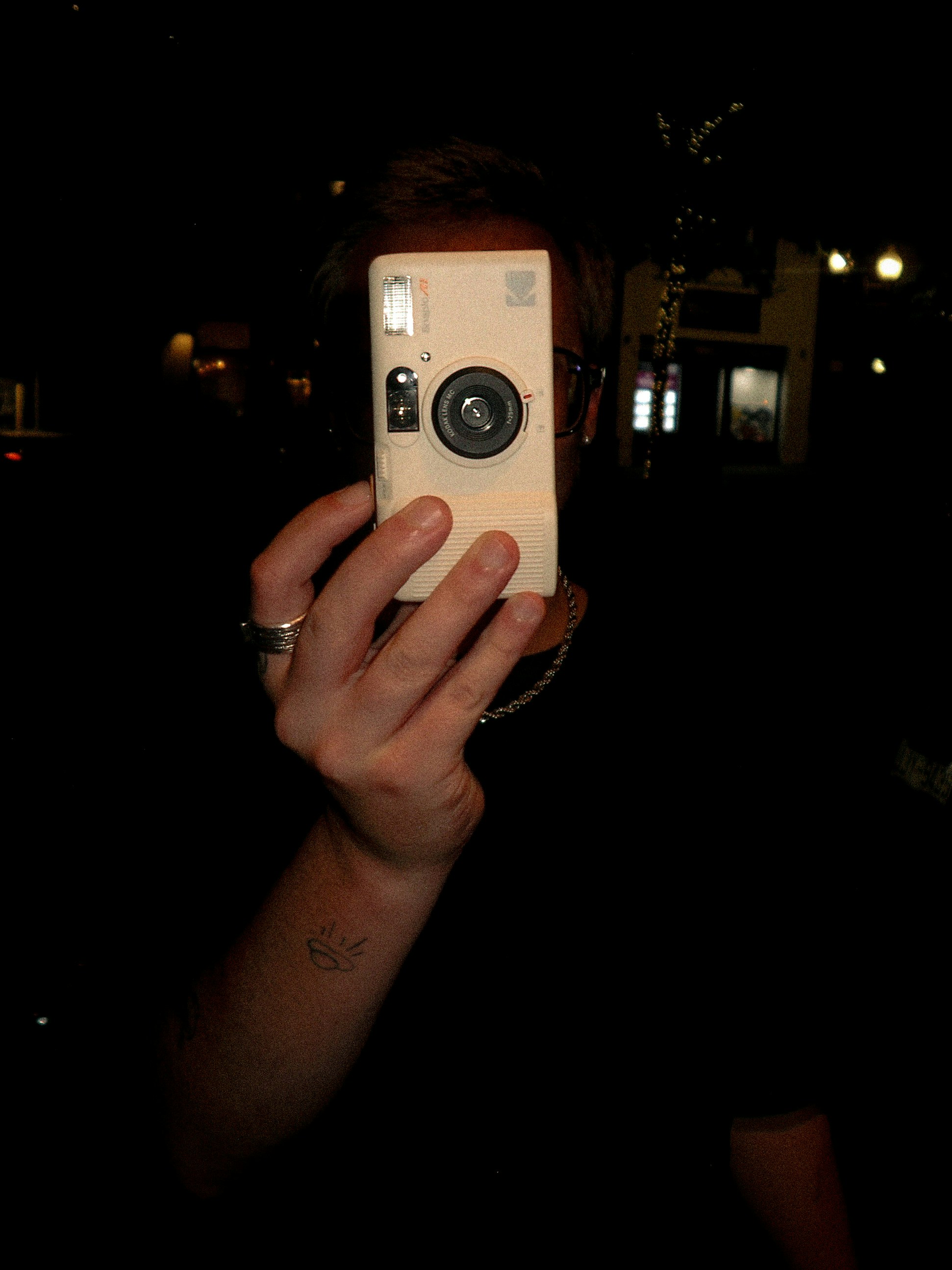 A person holding a small vintage camera in front of their face.