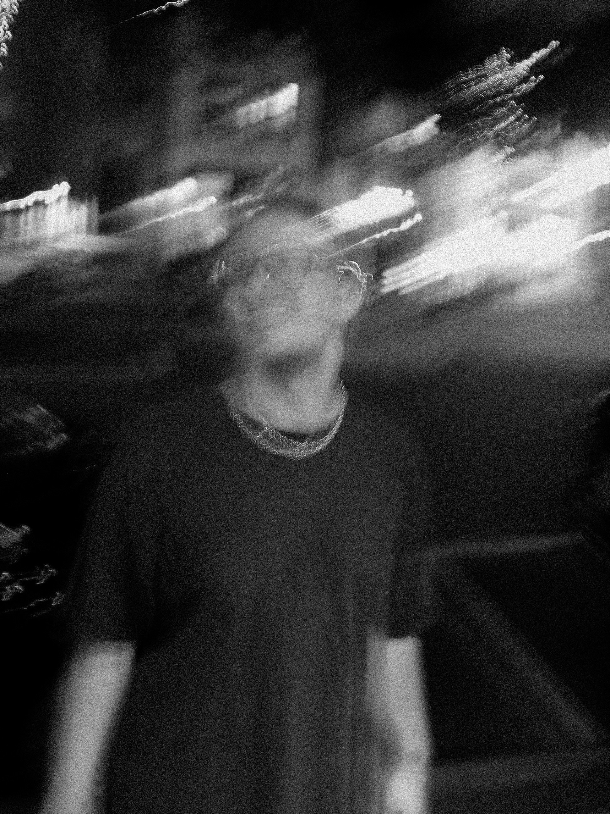 A person in glasses and a dark t-shirt with motion blur at night