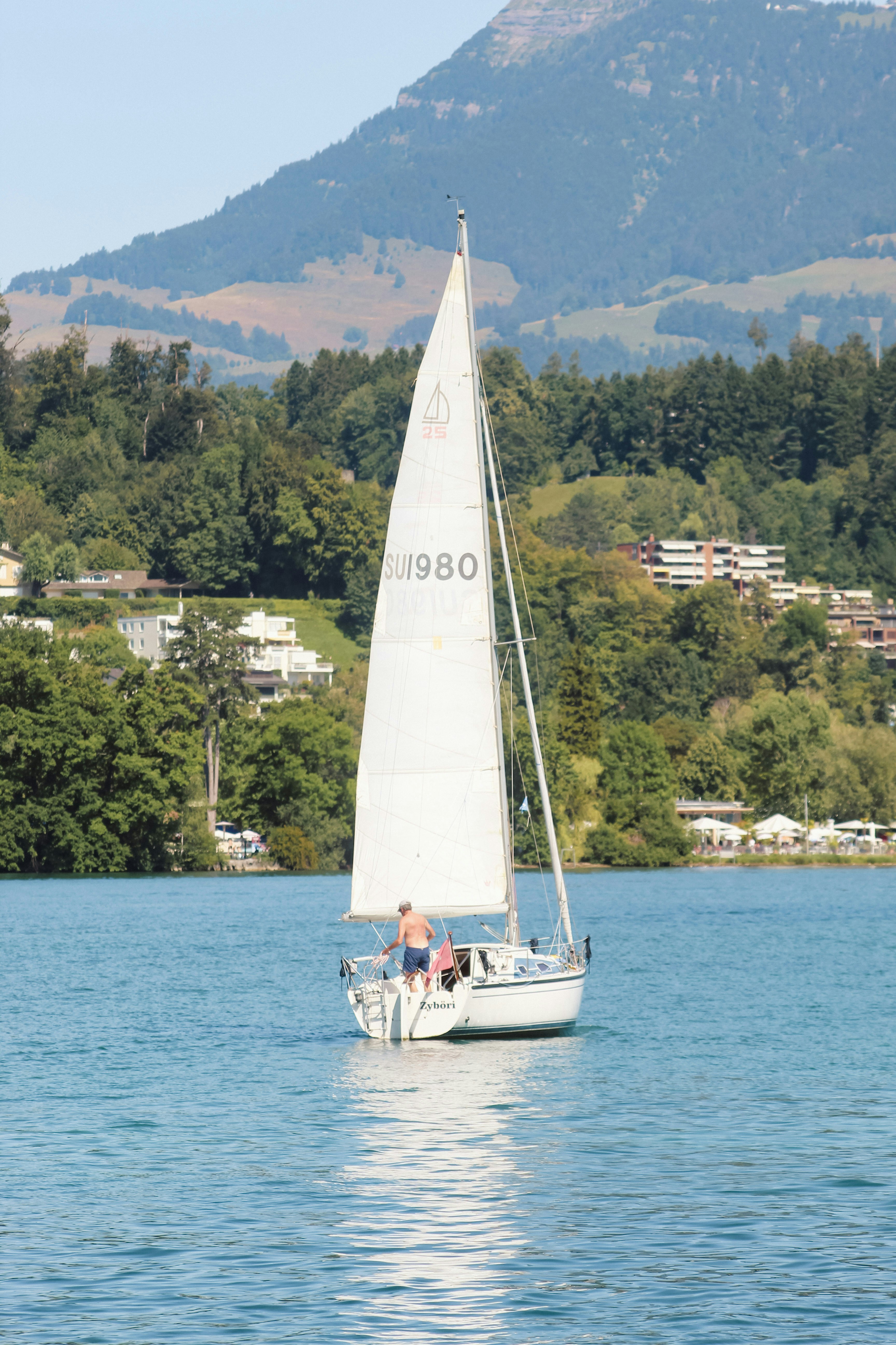 Sailboat Serene on a Glassy Lake Amid Mountain Backdrop