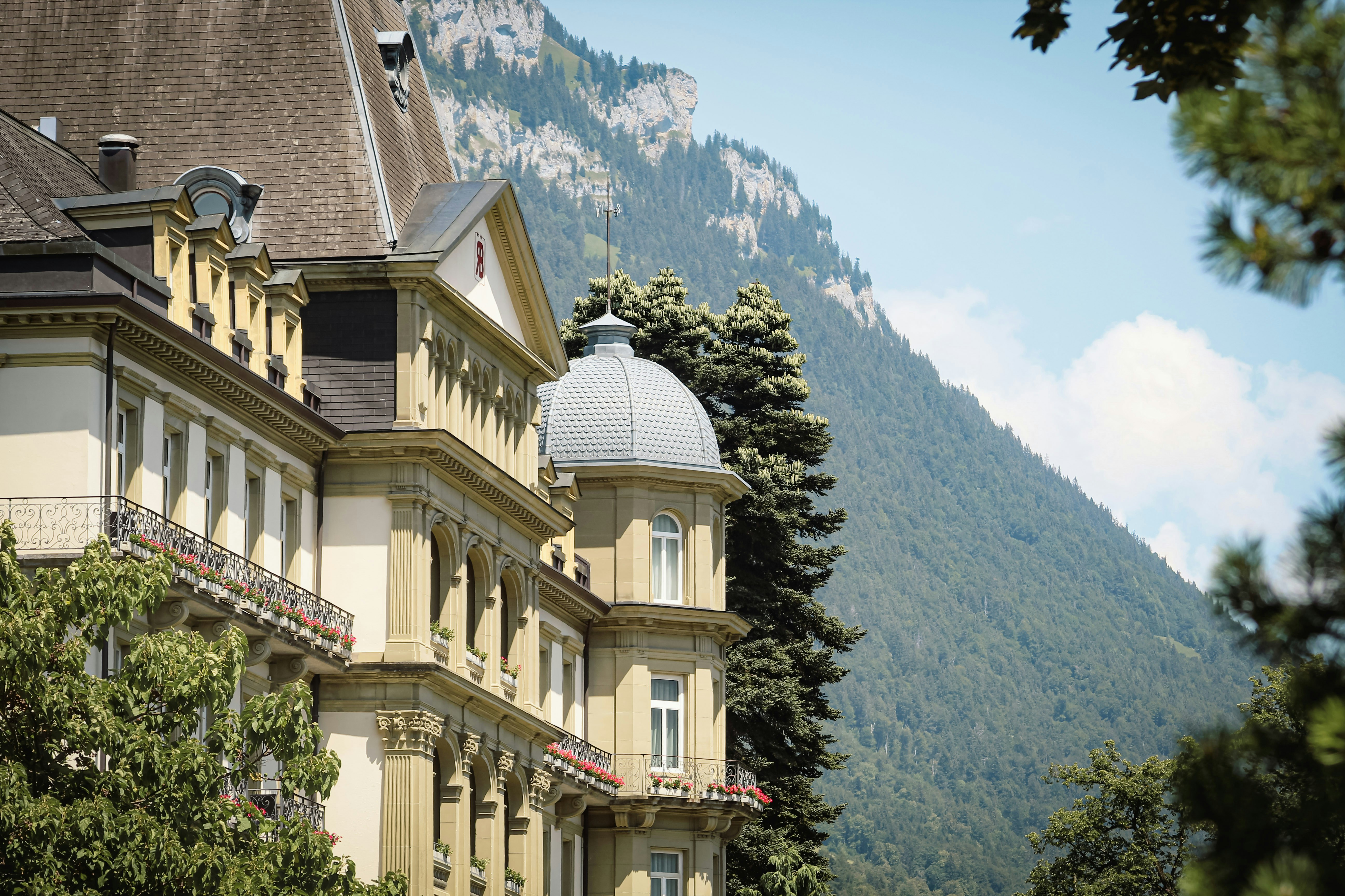 A grand alpine hotel basking in sun against a towering valley