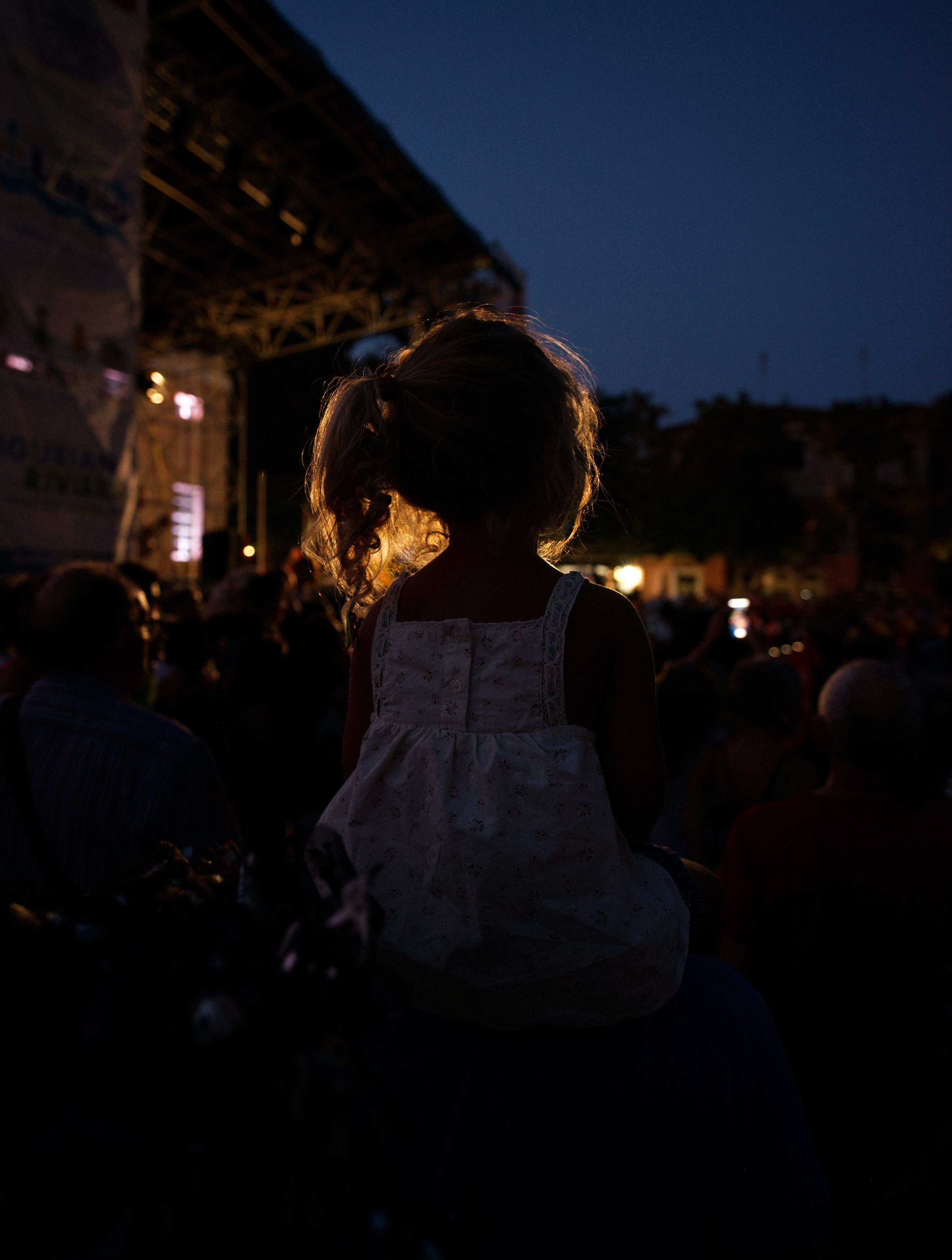 Backlit Child on Stage: A Silhouette Among Night Lights