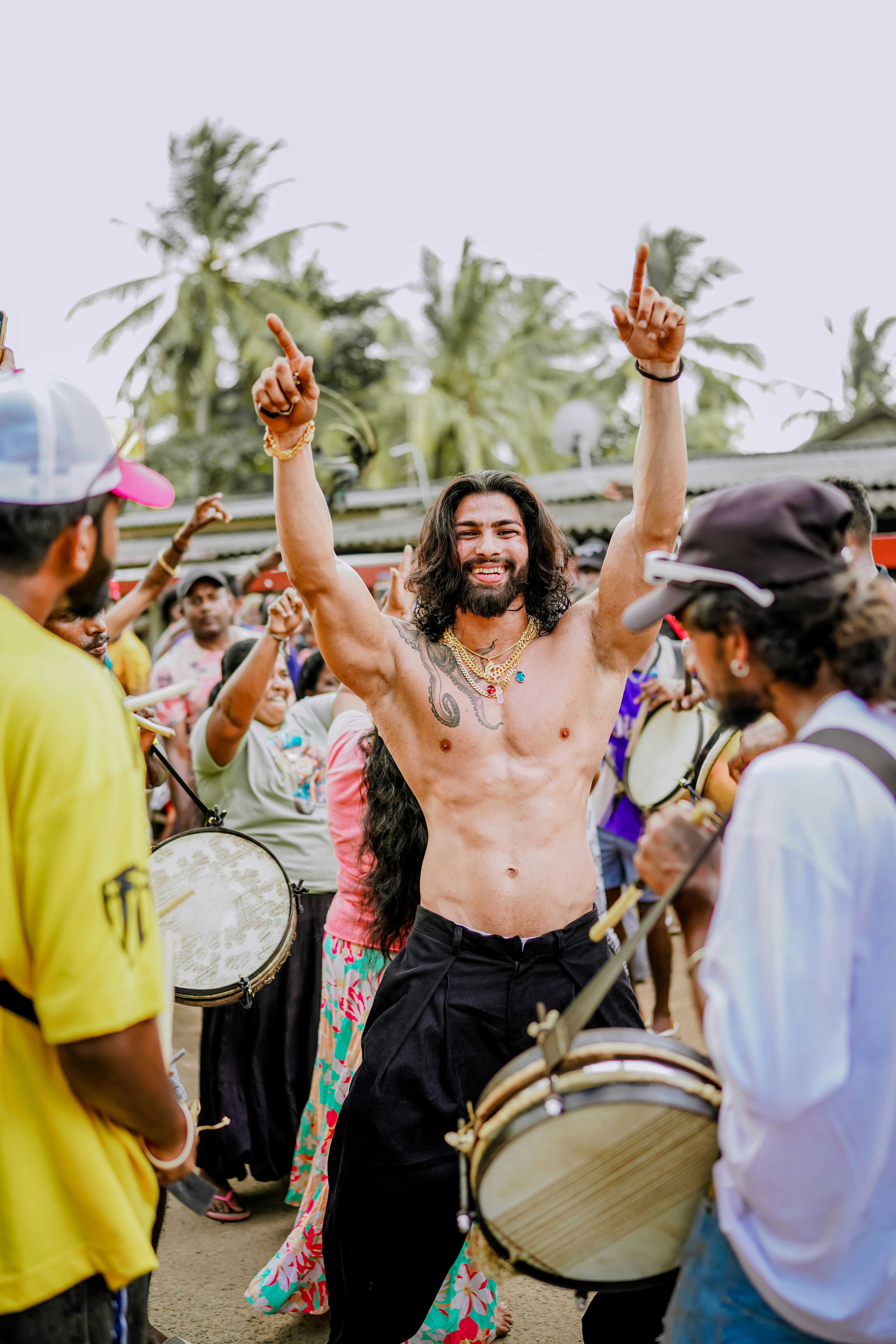 Center of Rhythm: A Shirtless Drum Leader Raises Hands Amid Crowd