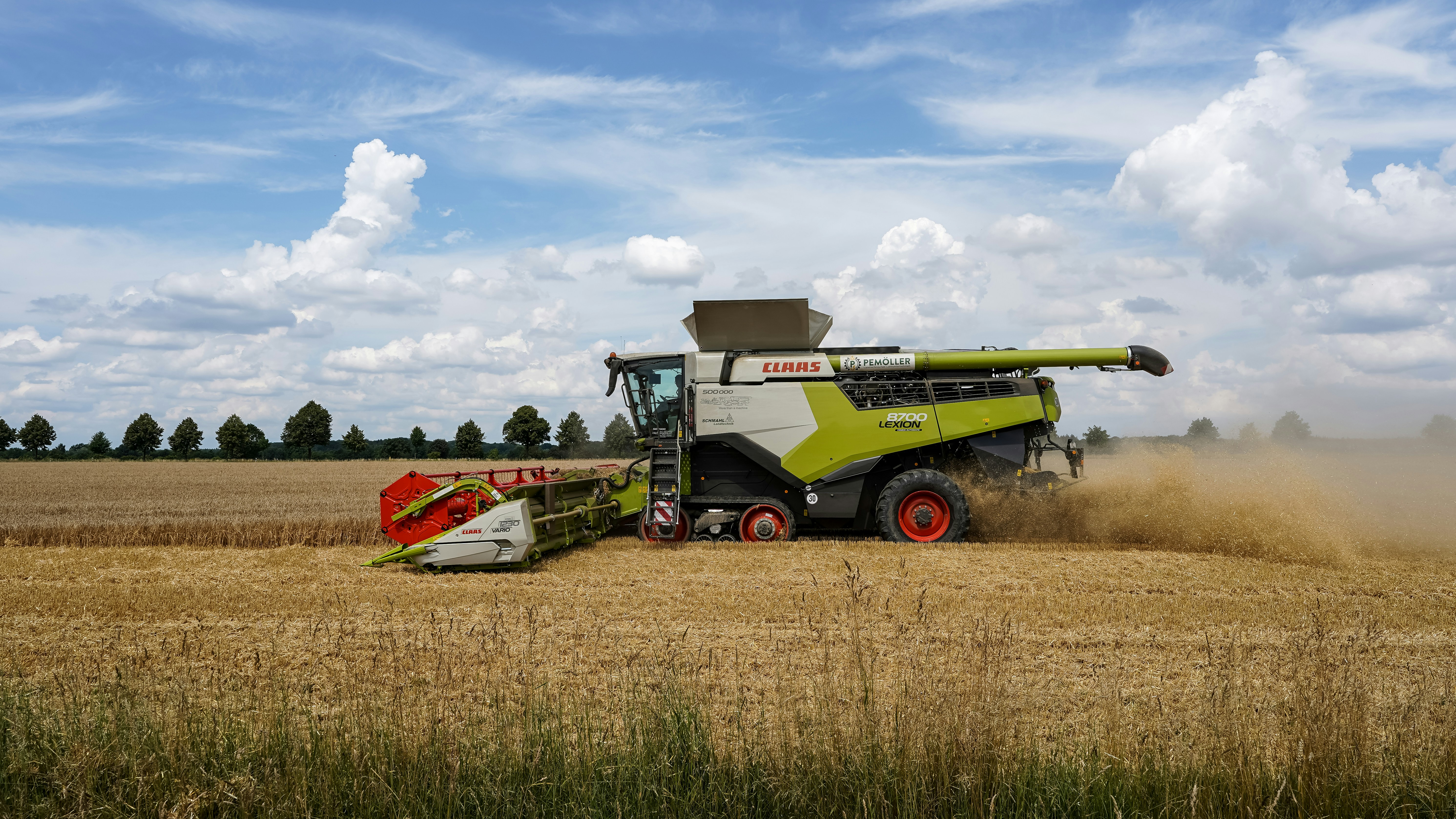 Harvest in Motion: Green Combine at Work Across a Golden Field