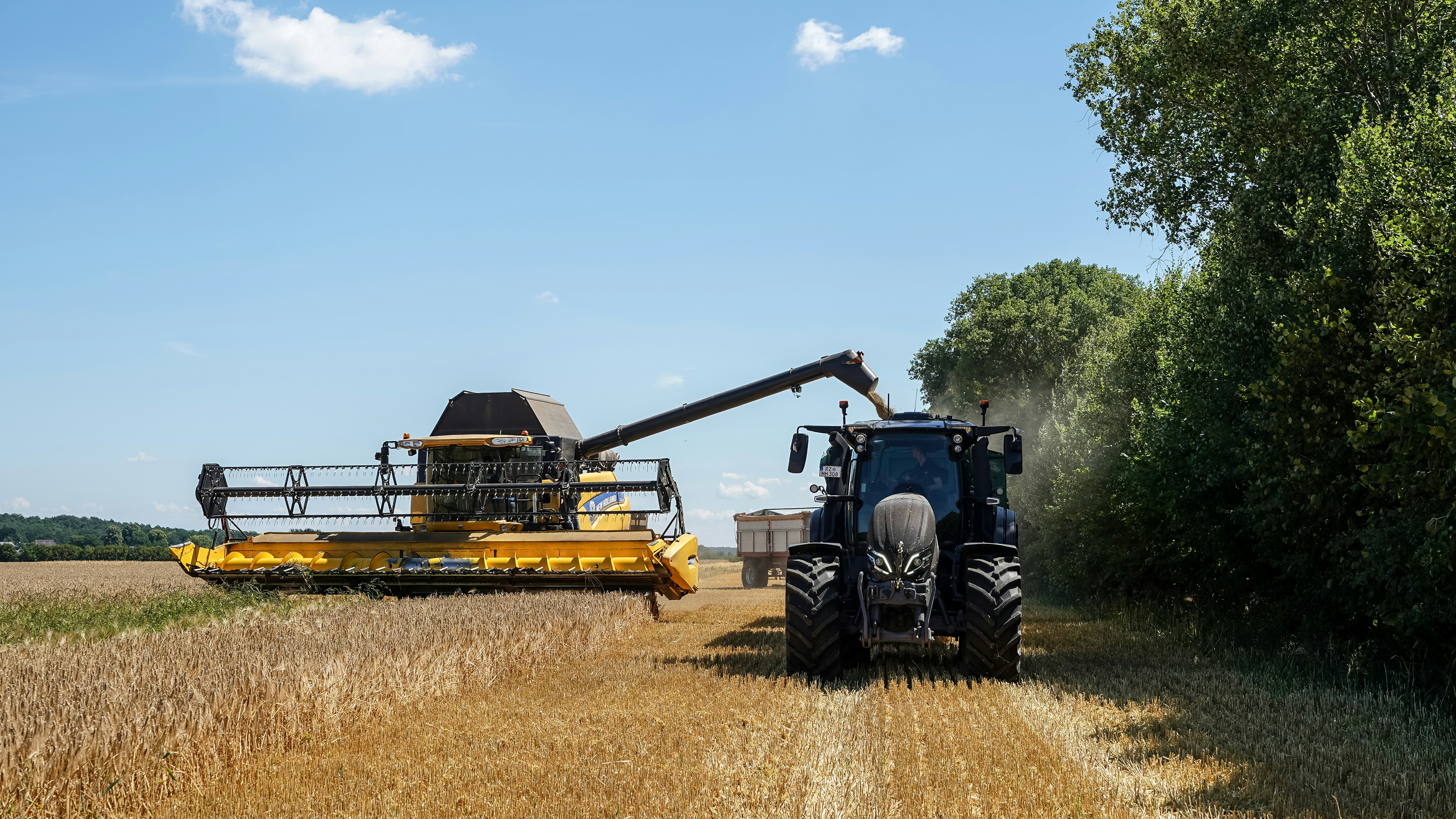 Harvest in the Field: The Combine Meets the Tractor at Dusk