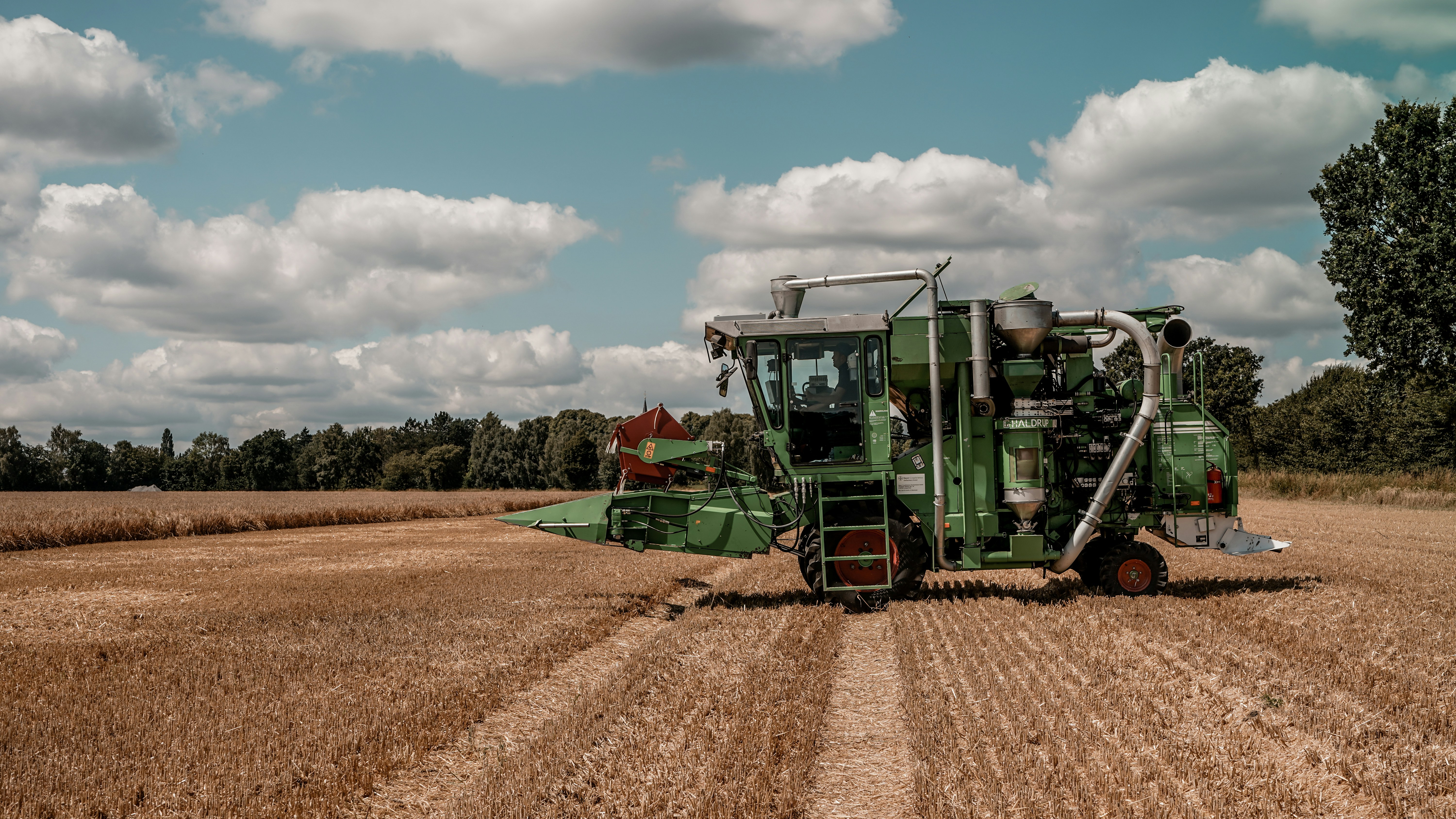 Harvest Machinery at Dusk: A Green Combine Resting in a Wheat Field