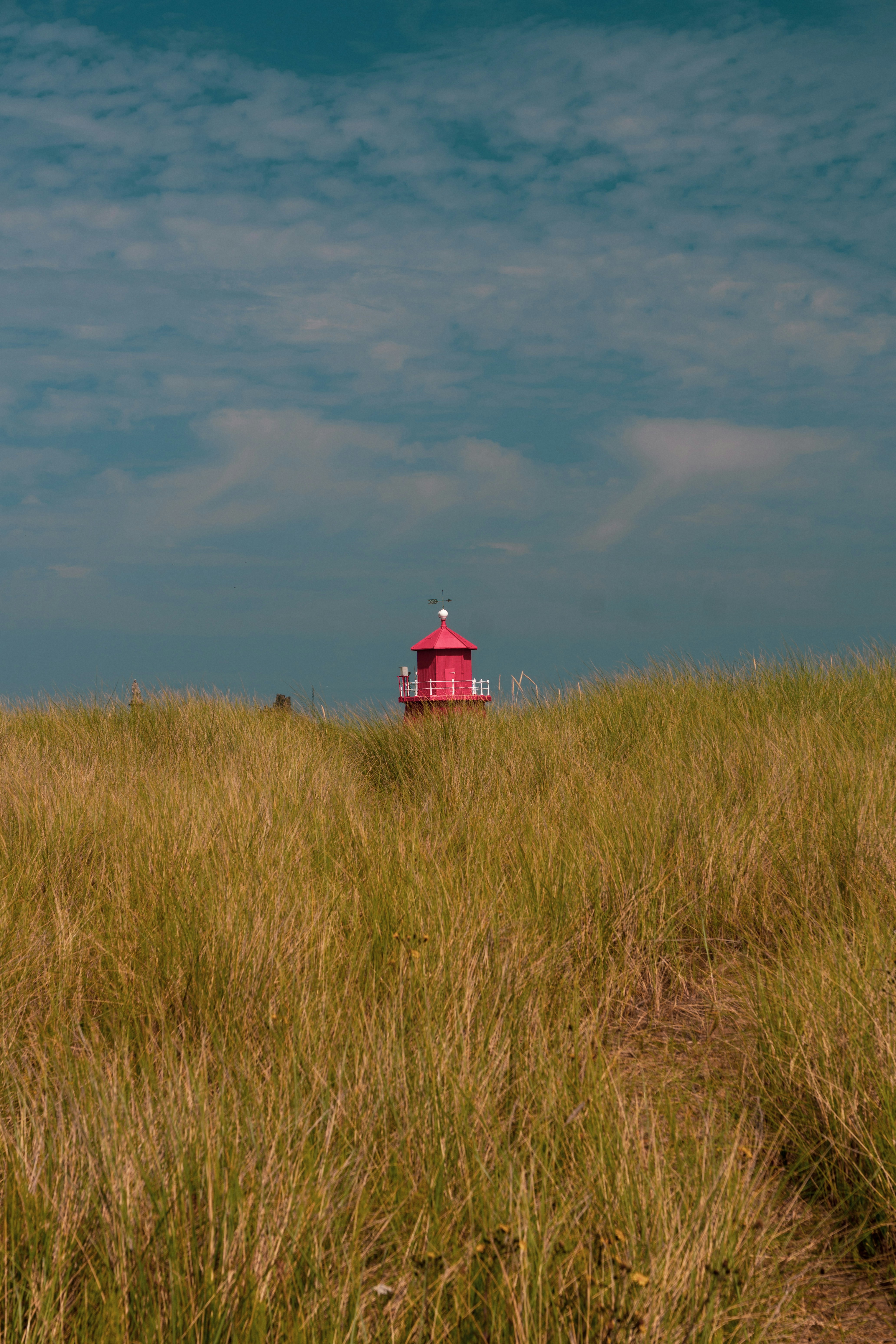 Red Beacon on the Dune: A Lone Lighthouse Over Sea Grass