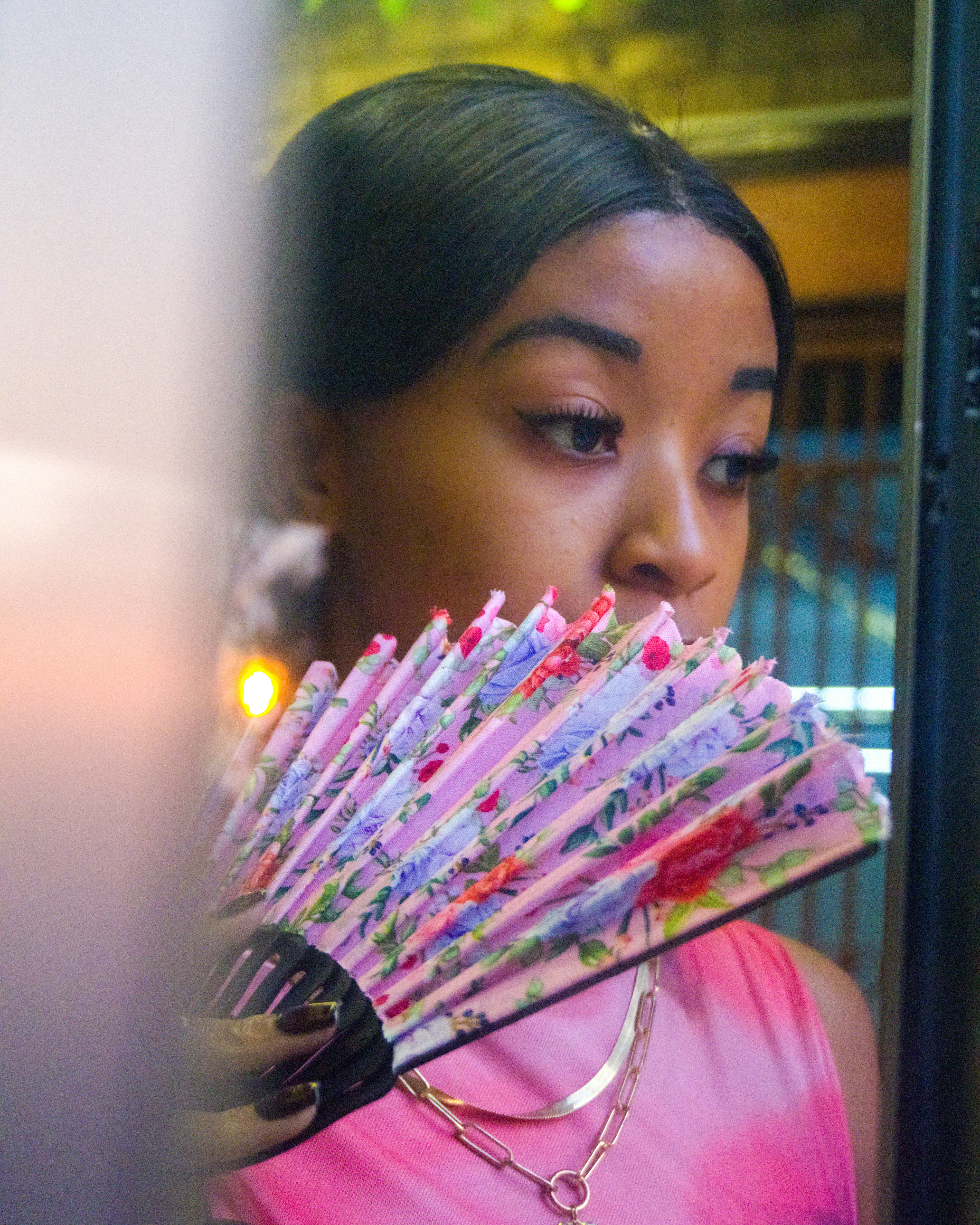 Portrait in Soft Neon: A Woman with a Floral Fan Peeking from the Frame