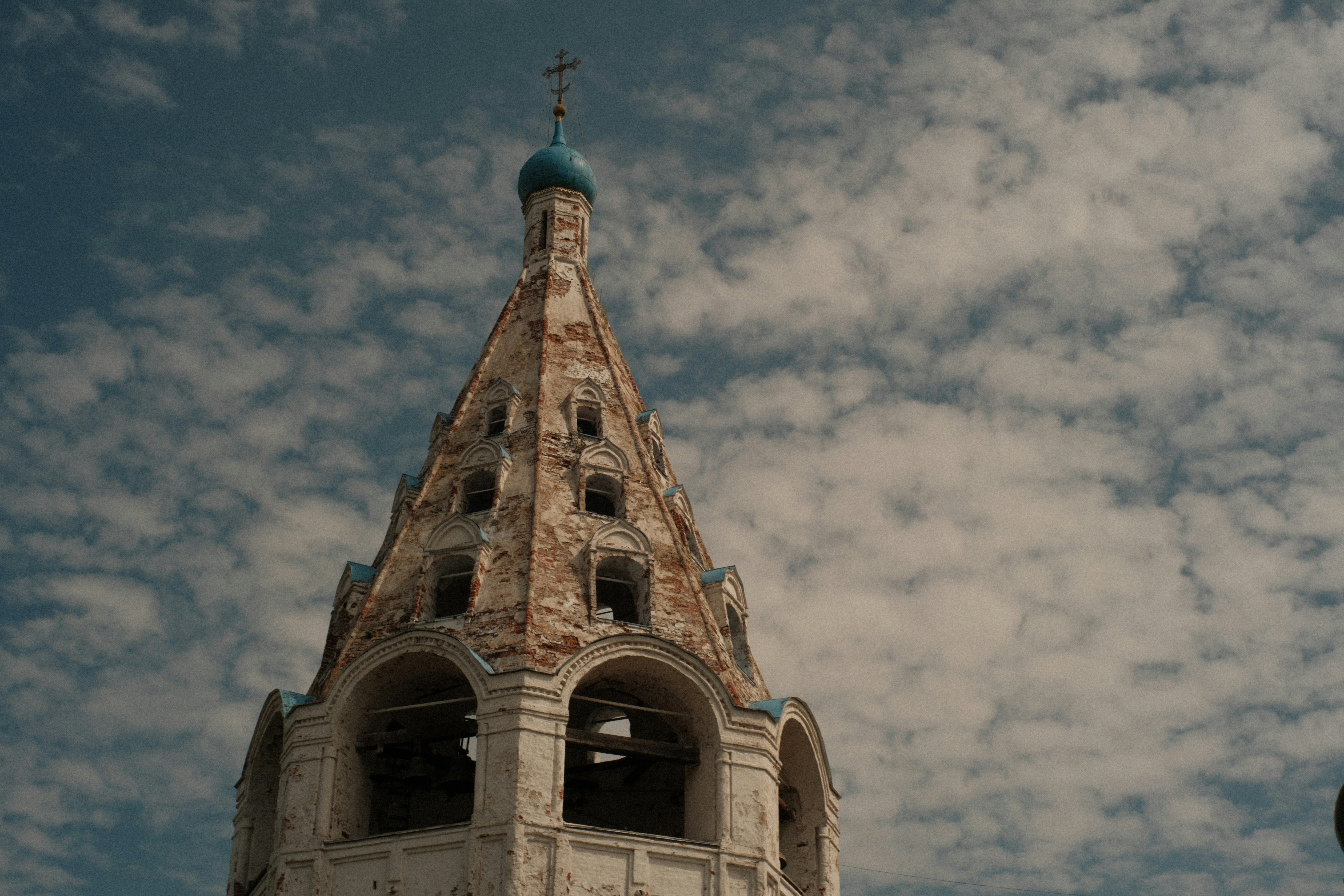 Weathered bell tower reaching toward a cloudy sky