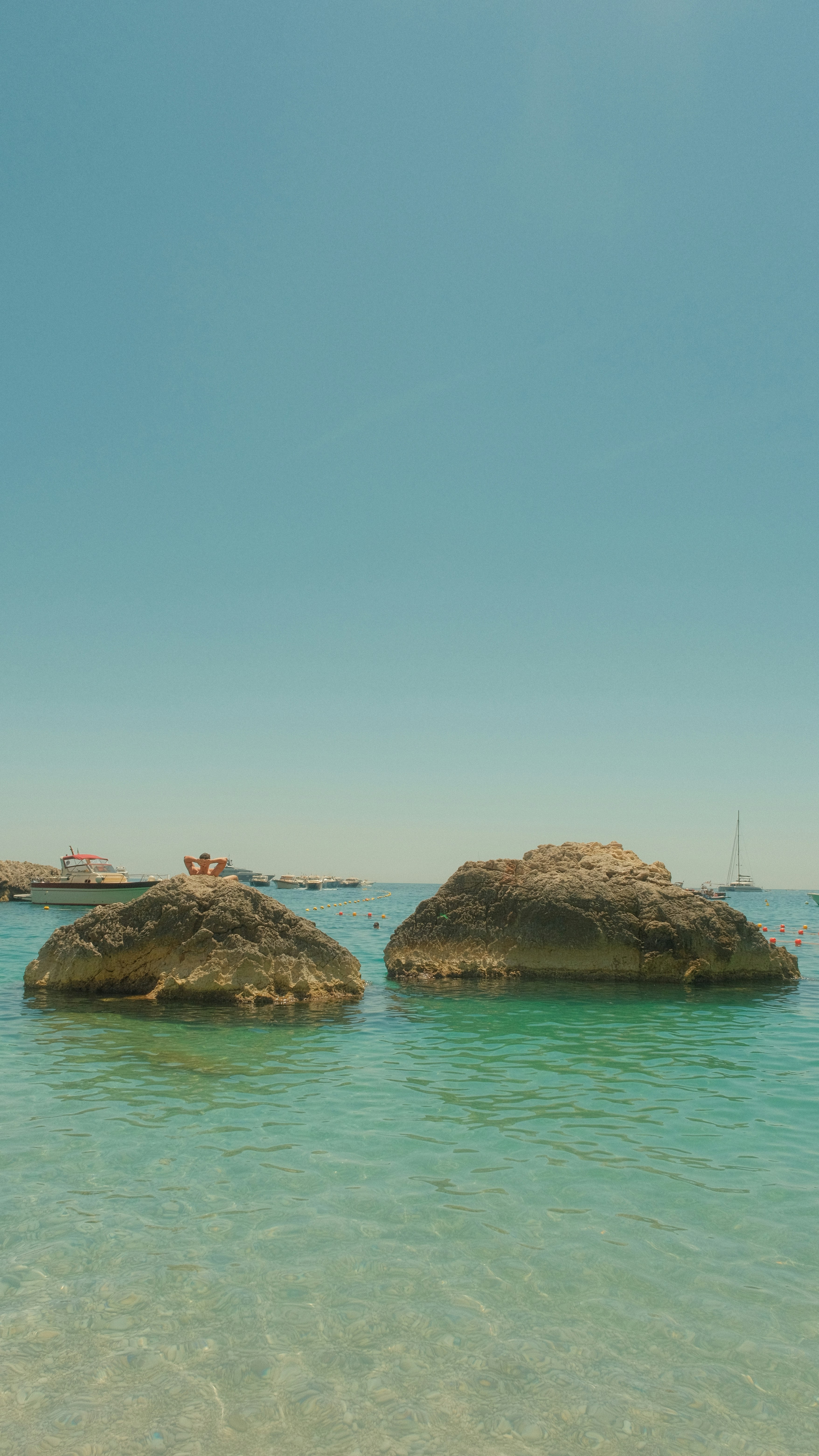 Sunlit Boulders Guard the Turquoise Shore