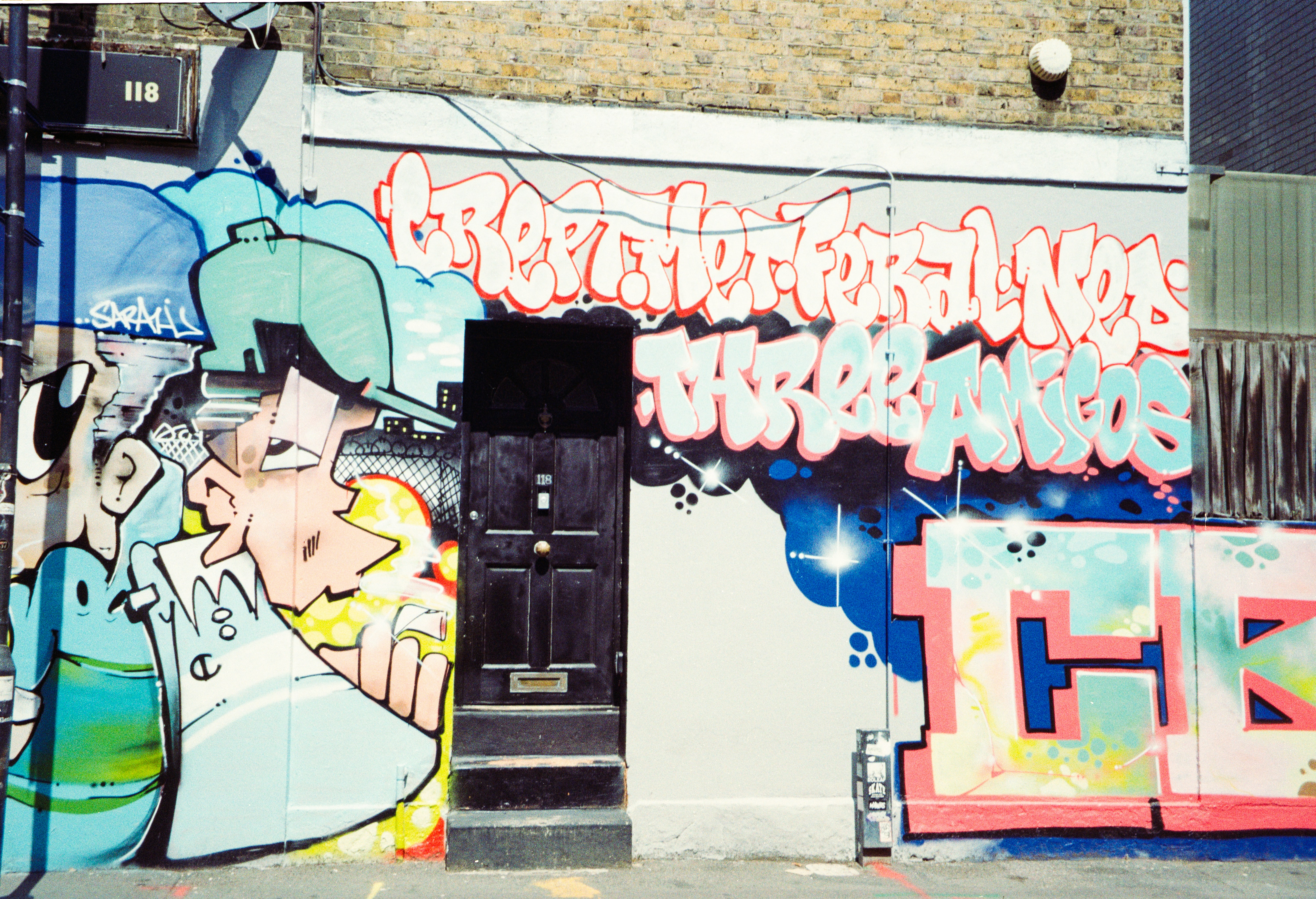 Graffiti Gallery Front: A City Wall with Vibrant Murals and a Central Door