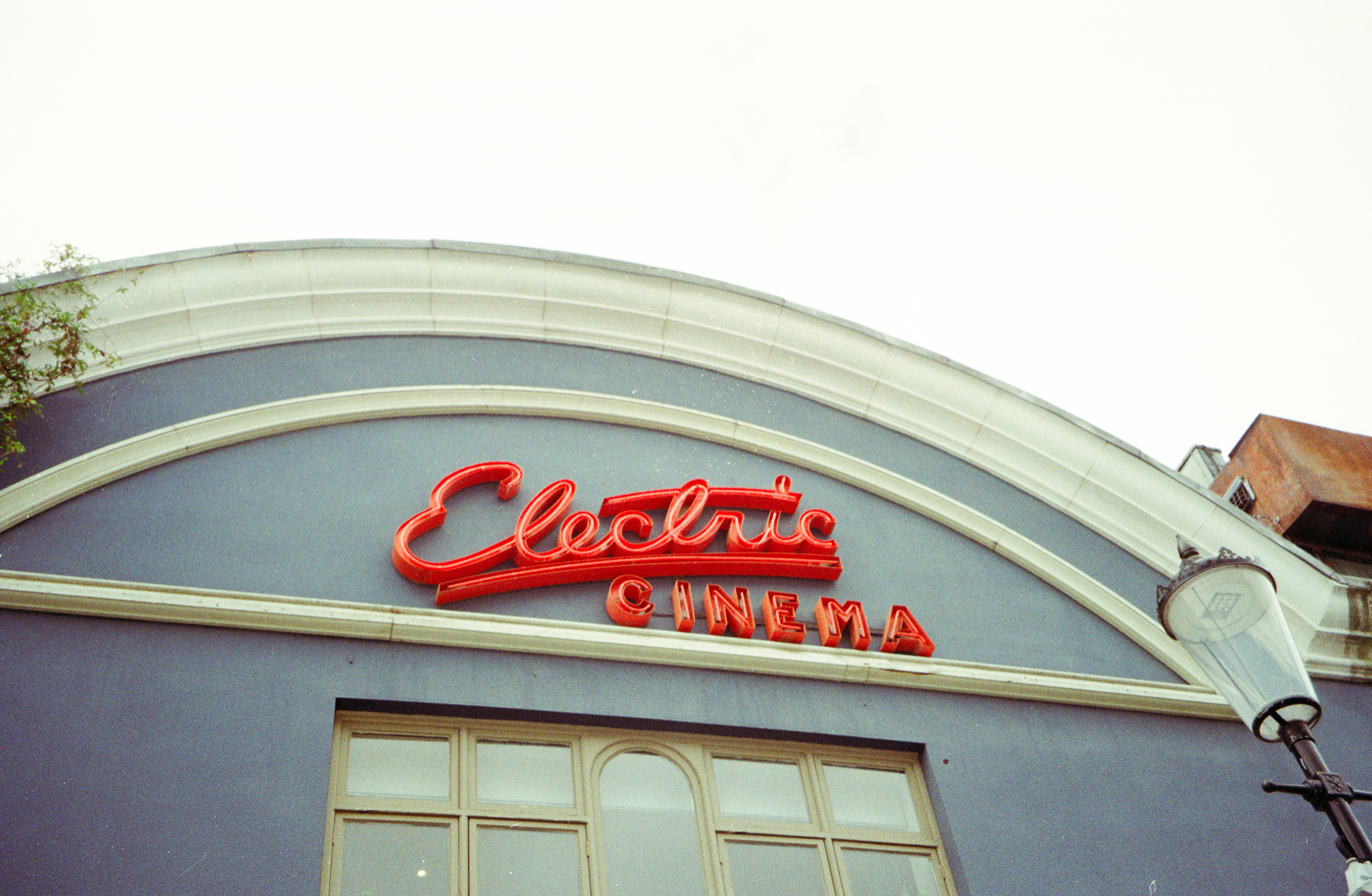 Neon Sign, Vintage Facade: Electric Cinema Under Soft Sky