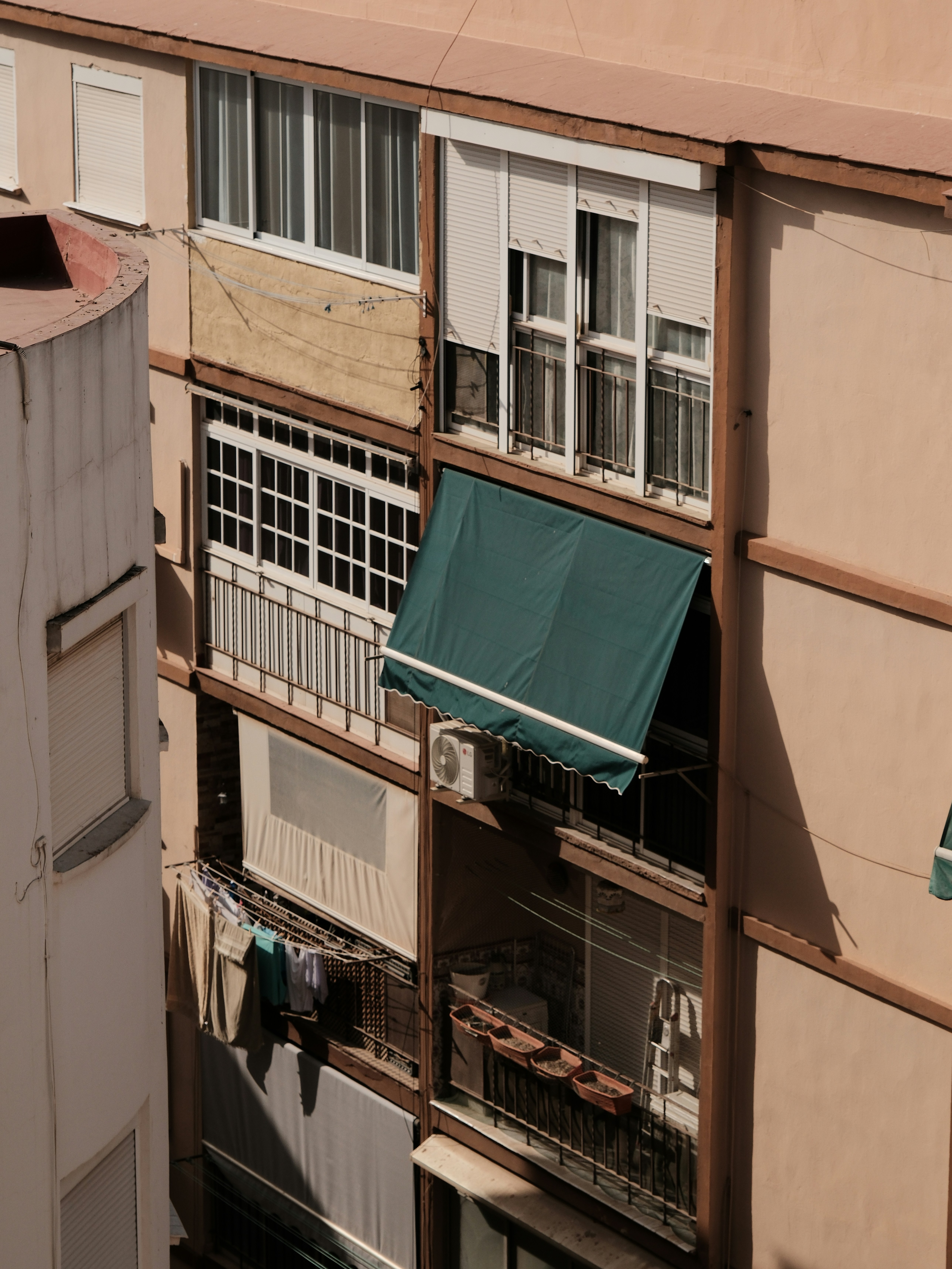 Sunlit Balcony: A Close-Up of a Building's Green Canopy and Laundry Diffusion