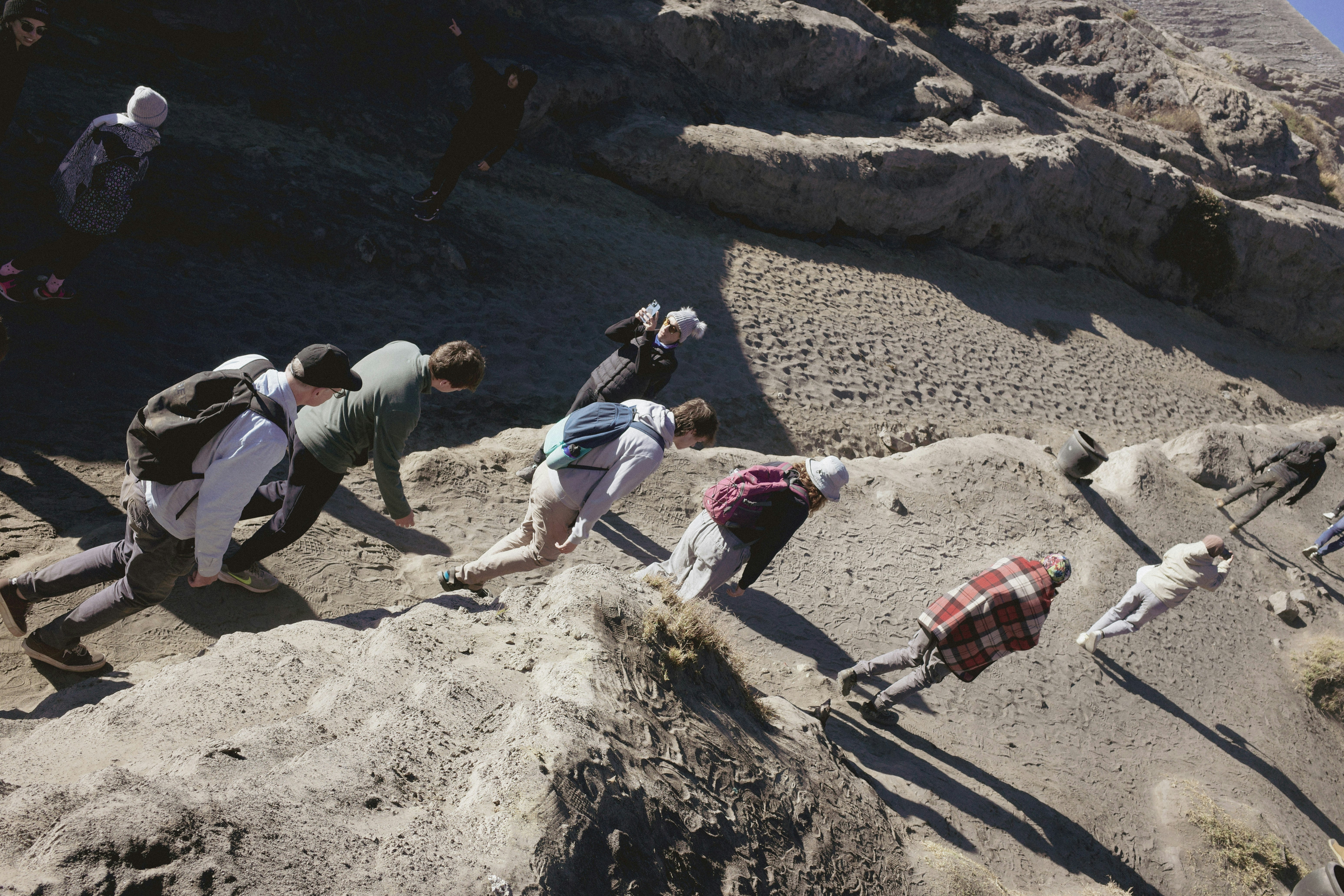 Climbing the rocky strip: a line of hikers tracing a sunlit ridge