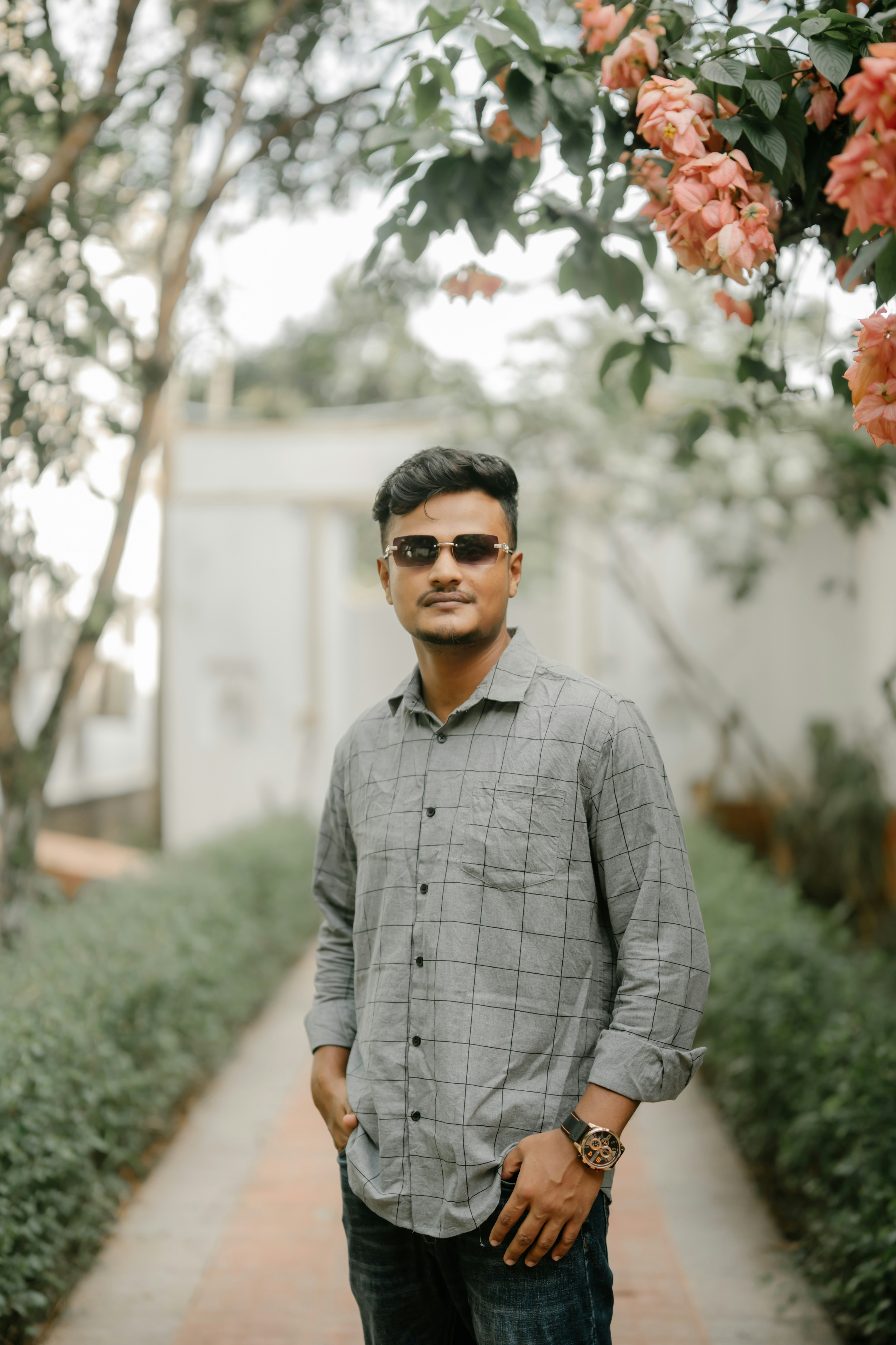 Portrait beneath blossom-laden canopy with a confident traveler in grid-pattern shirt