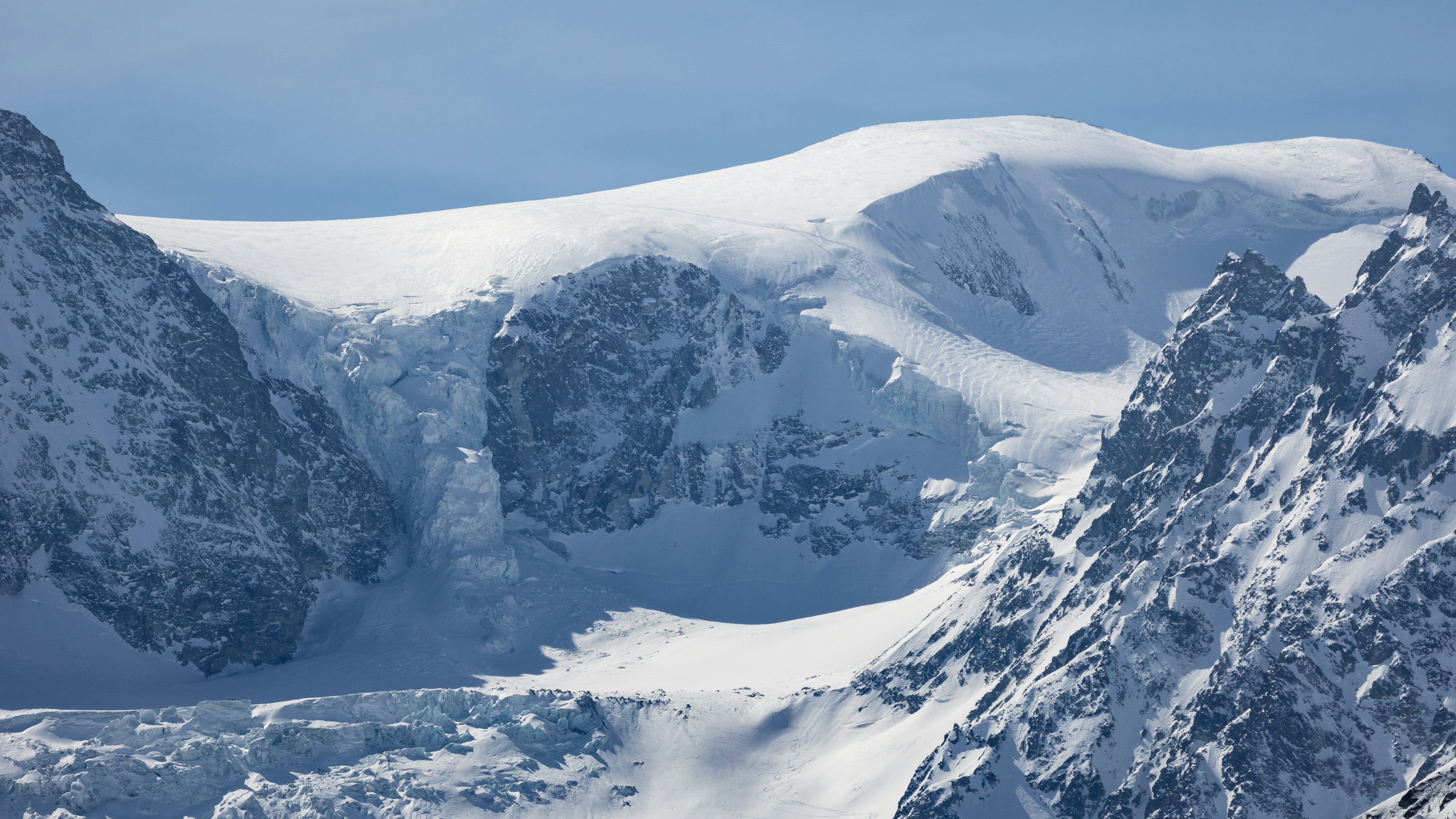 Glacier's Crown: A Majestic Snowbound Ridge Under Clear Skies