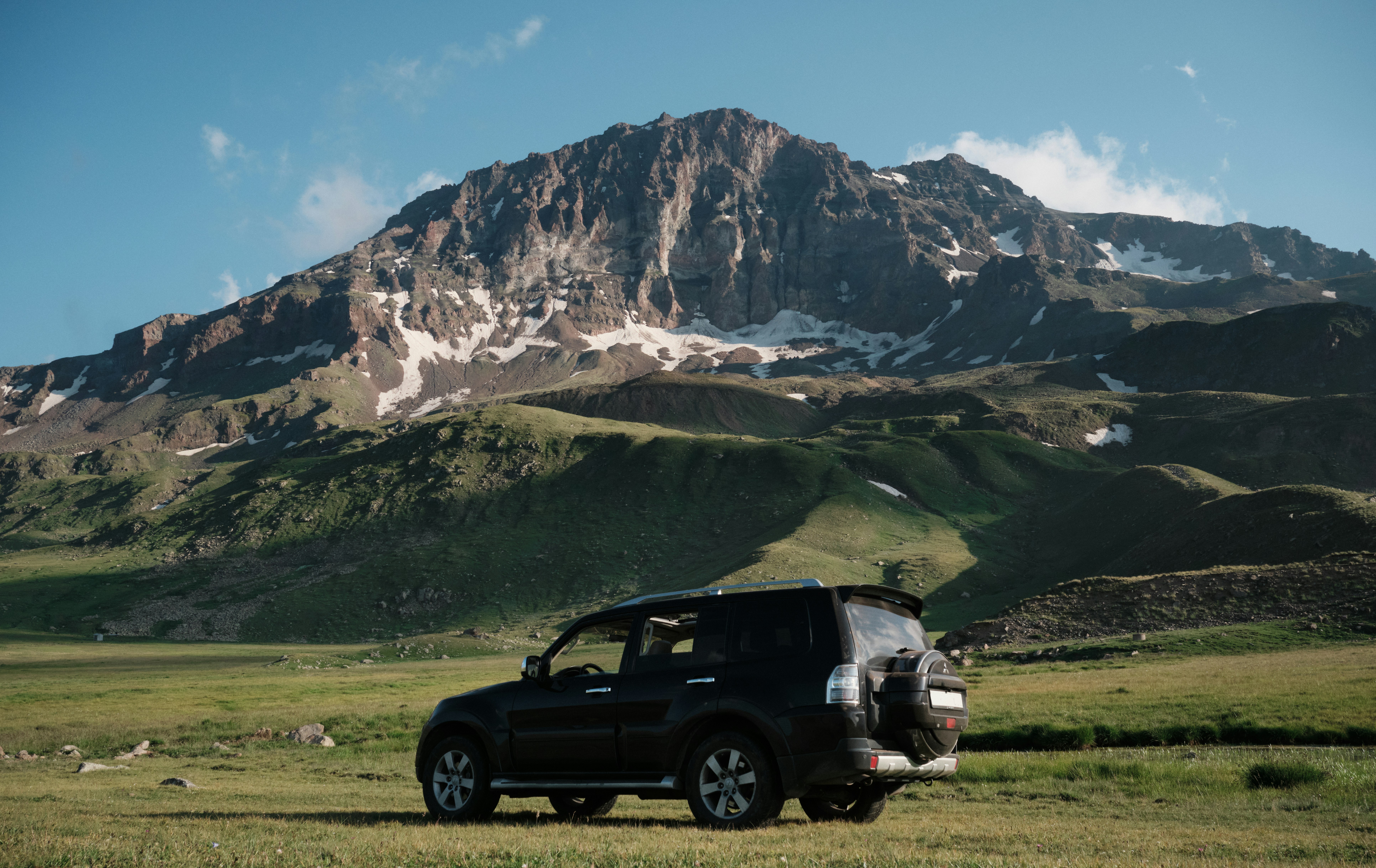 All-Terrain Vista: SUV at the Foot of Rugged Peaks