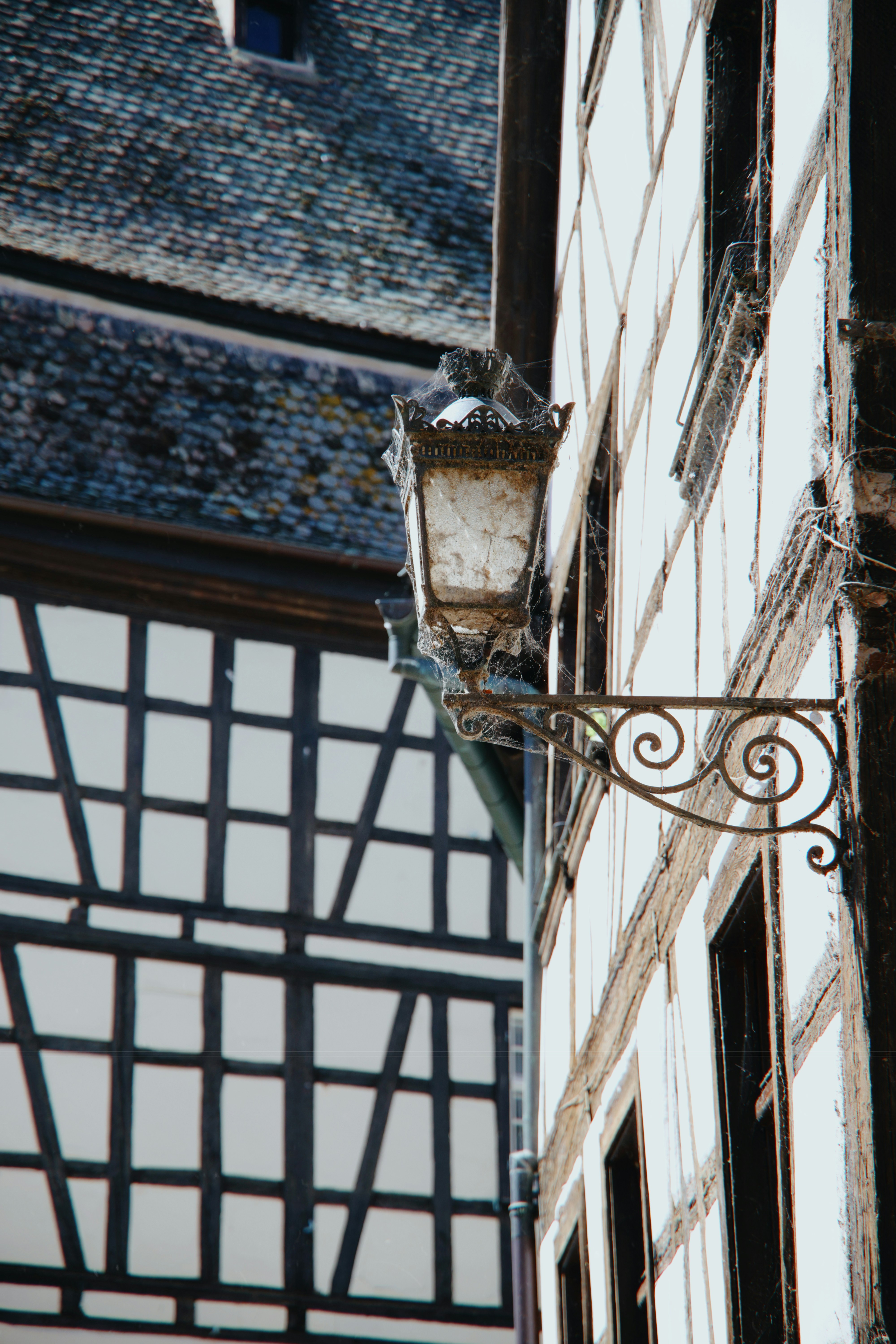 Ornate Lantern on a Historic Facade: A Draped Light Amid Timbered Architecture