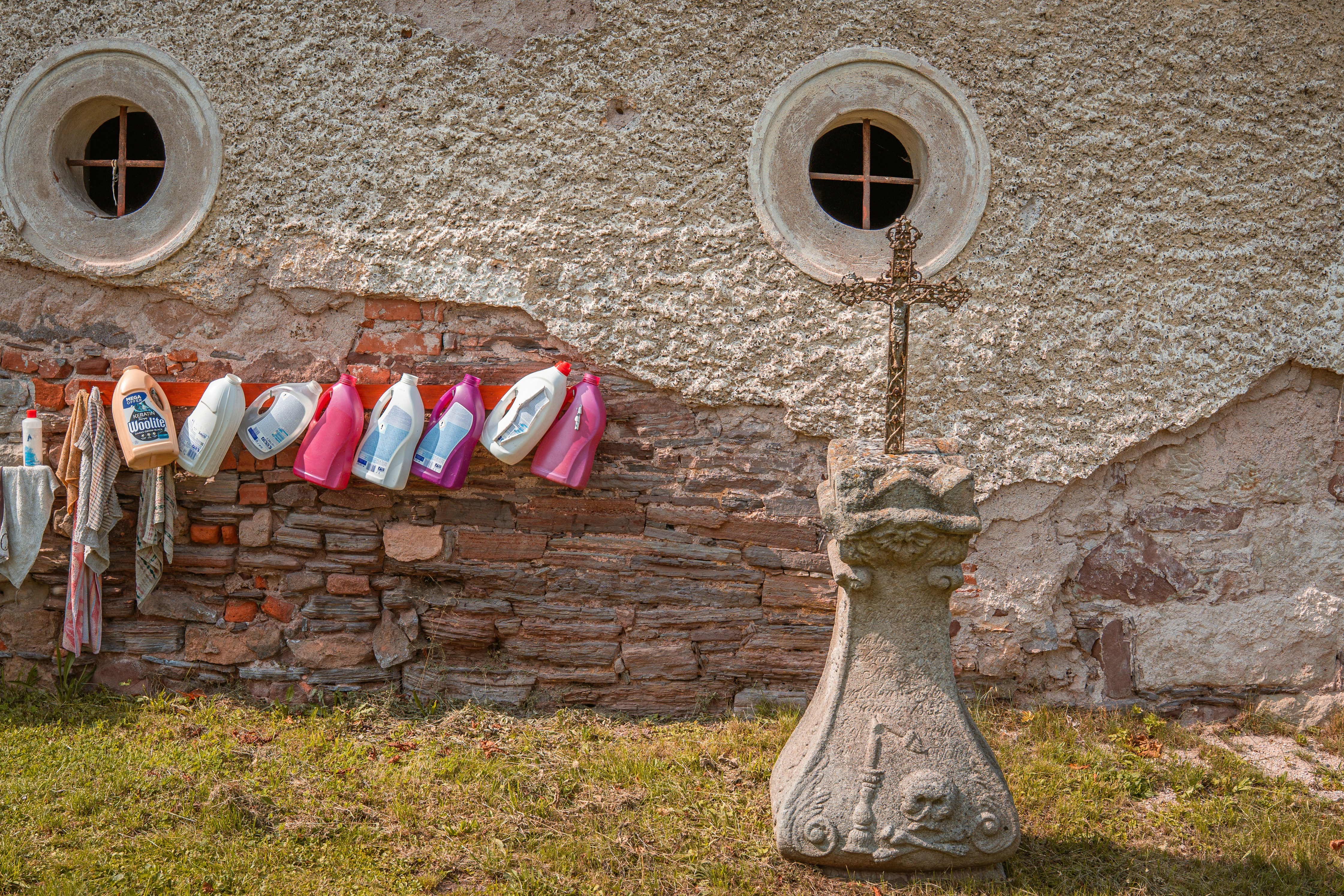 Colorful Laundry Line and Ancient Urn by Sunlit Stone Wall