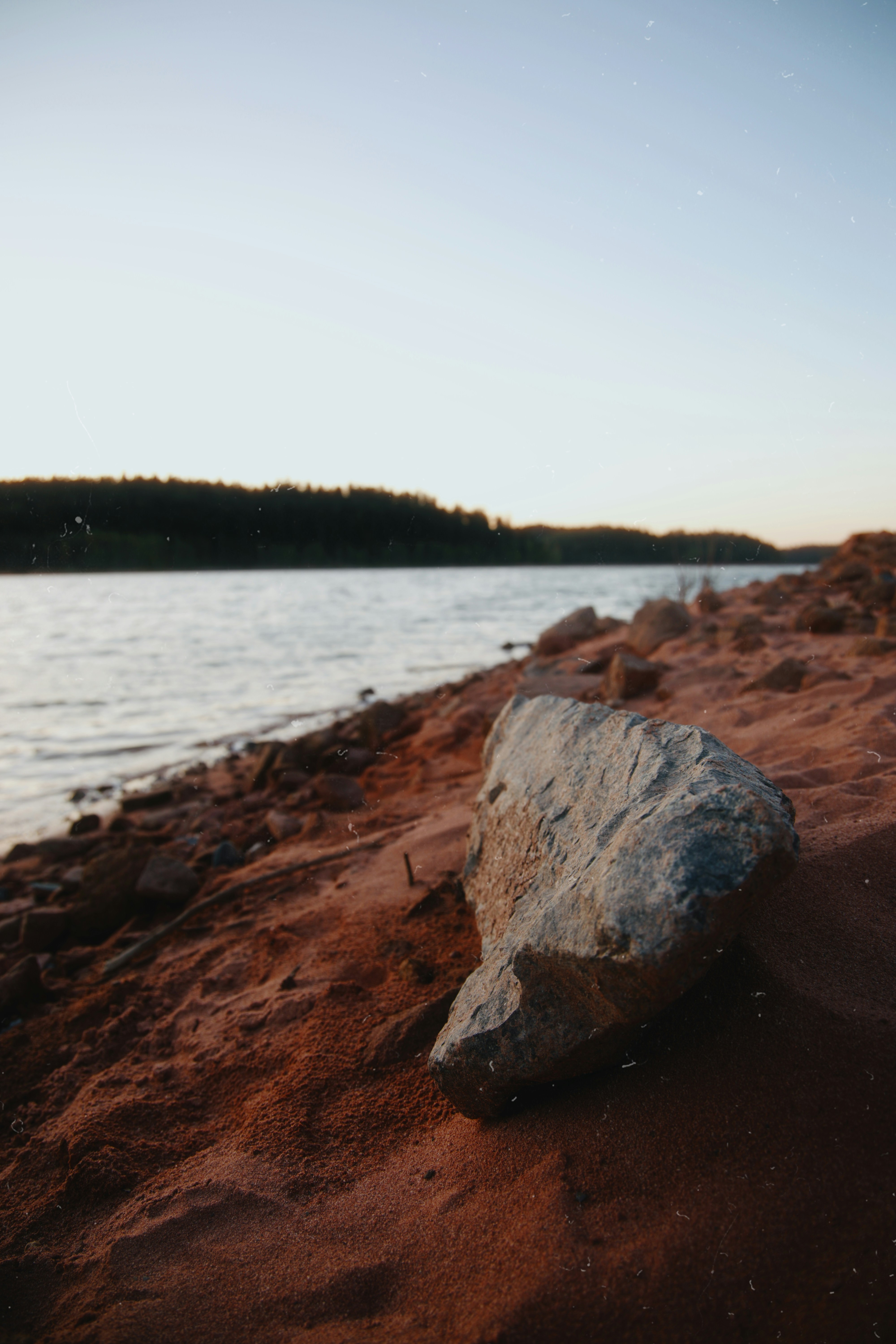 Rugged shoreline at dusk: a weathered rock anchors the shore