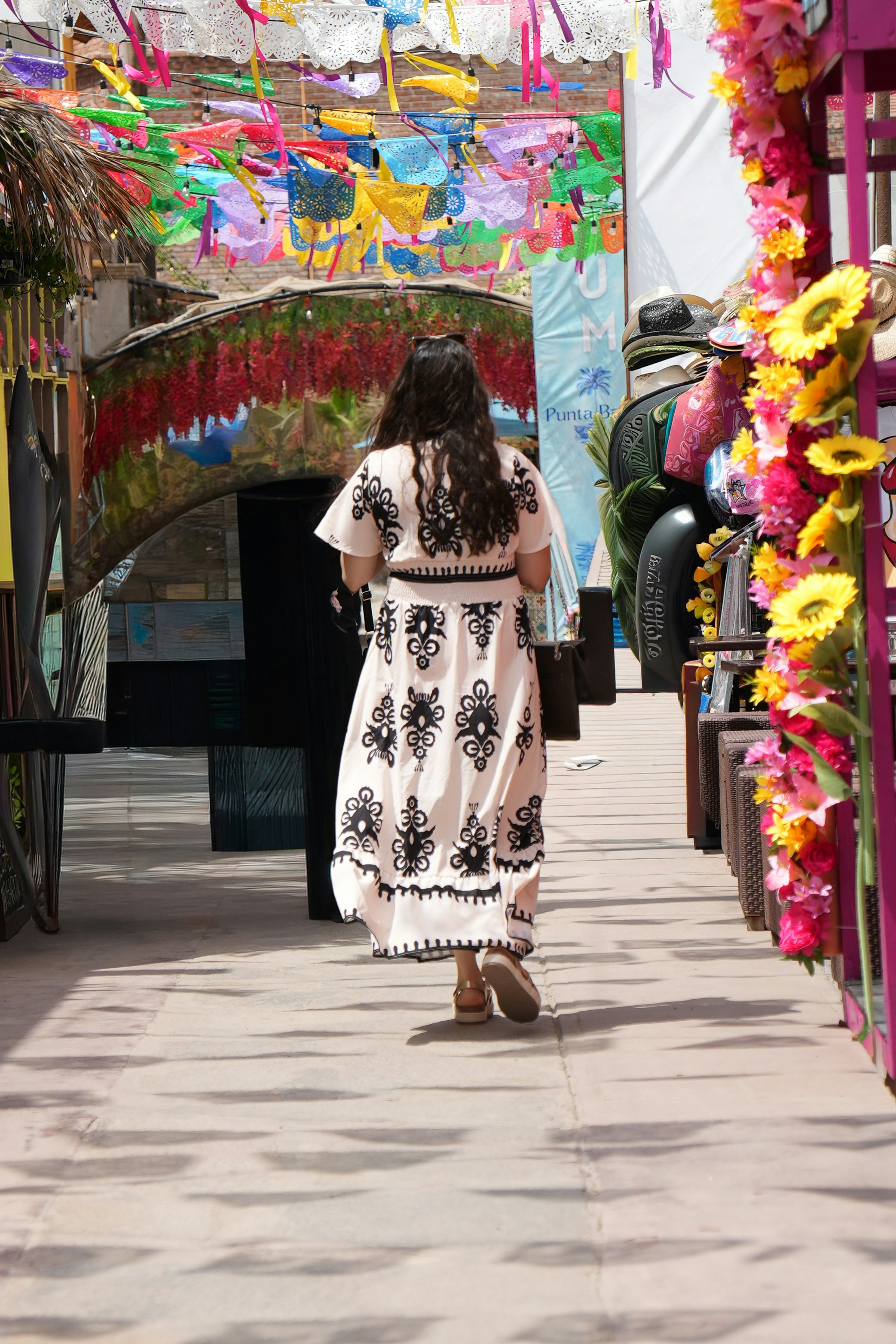 A White-Print Dress Walks Through a Festive Market Corridor