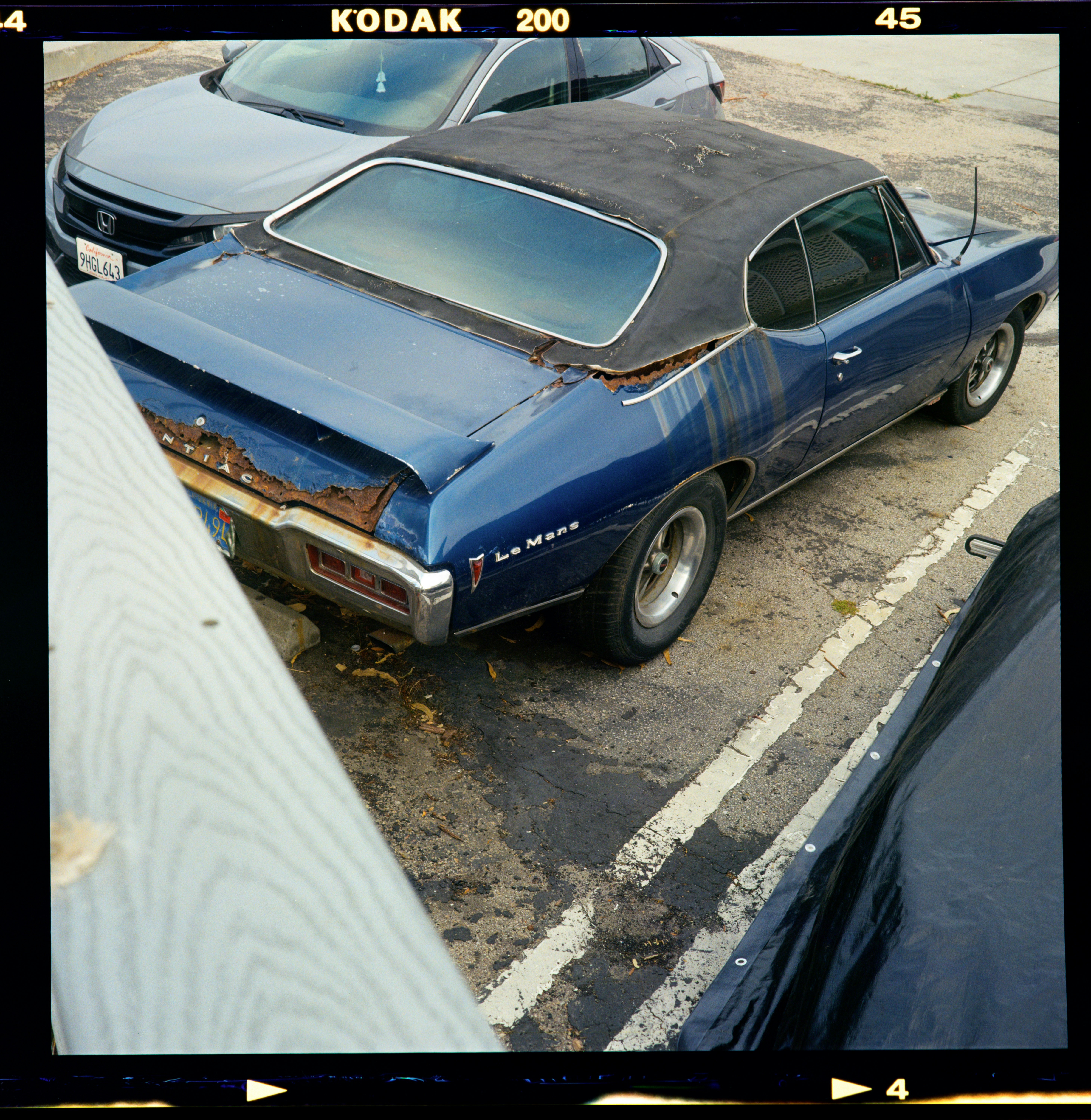 Rust and Blue: A Classic Camaro in a Weathered Parking Lot