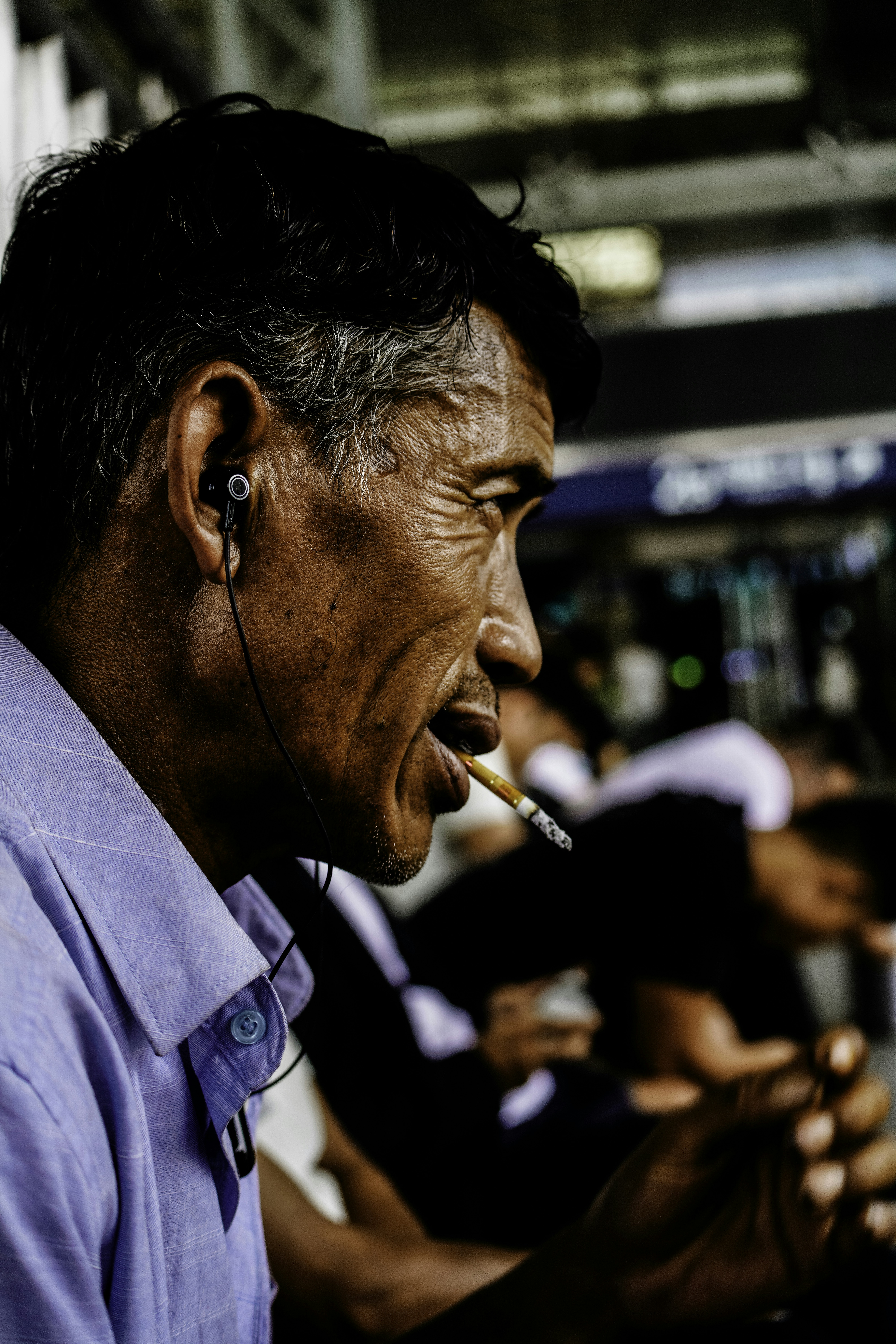 Cigarette, Earbud, and Focus: A Candid Moment in Transit