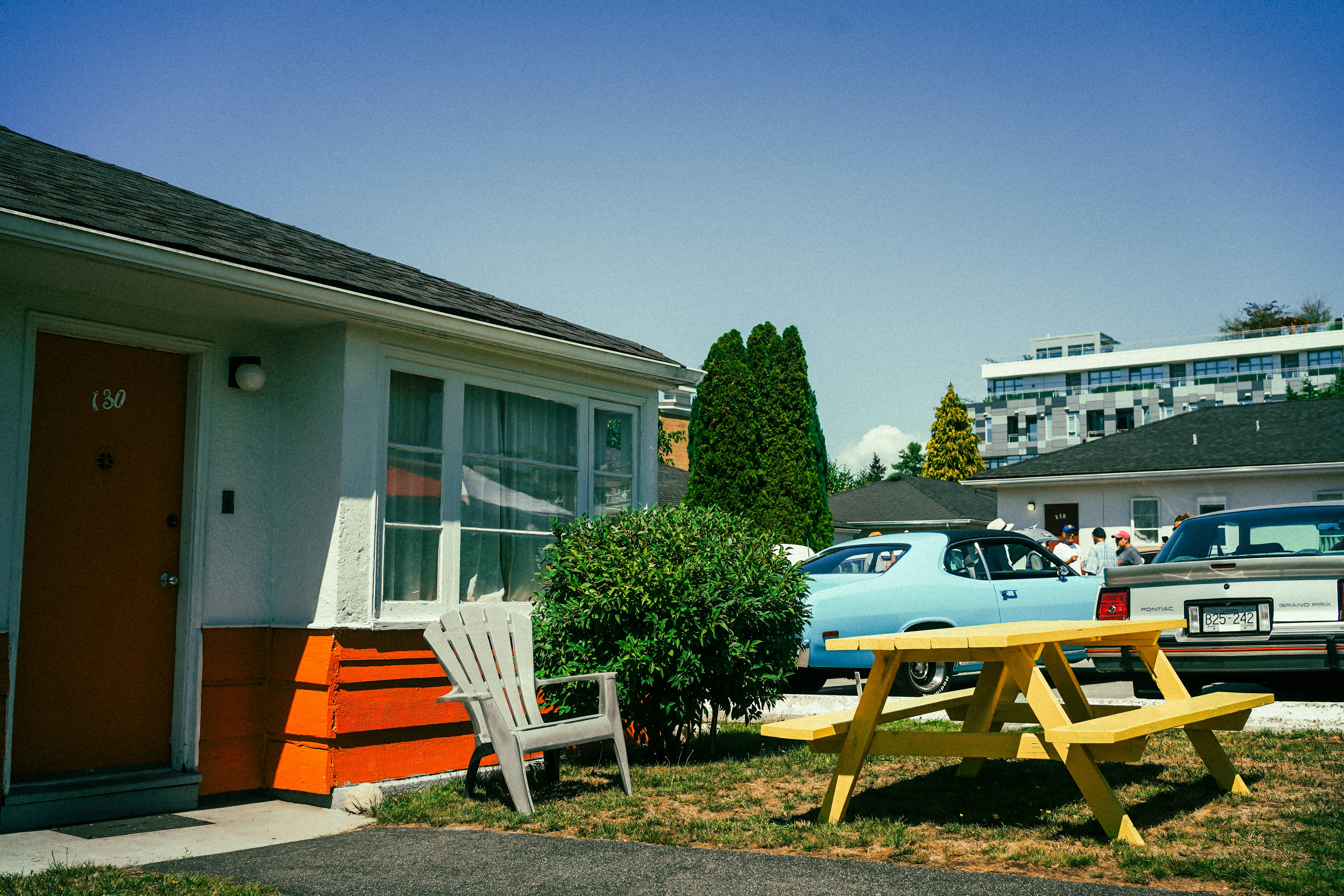 A yellow picnic table and grey chair outside a motel with orange doors