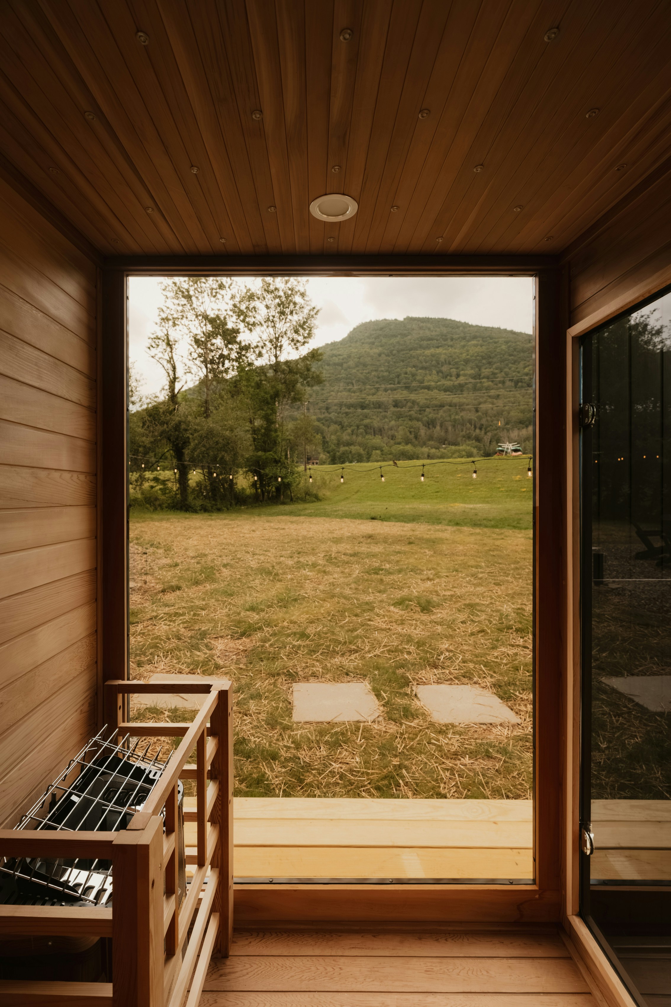 Frame to the Outdoors: A Wood-Panelled Gateway Looking Past a Lawn to a Green Hill